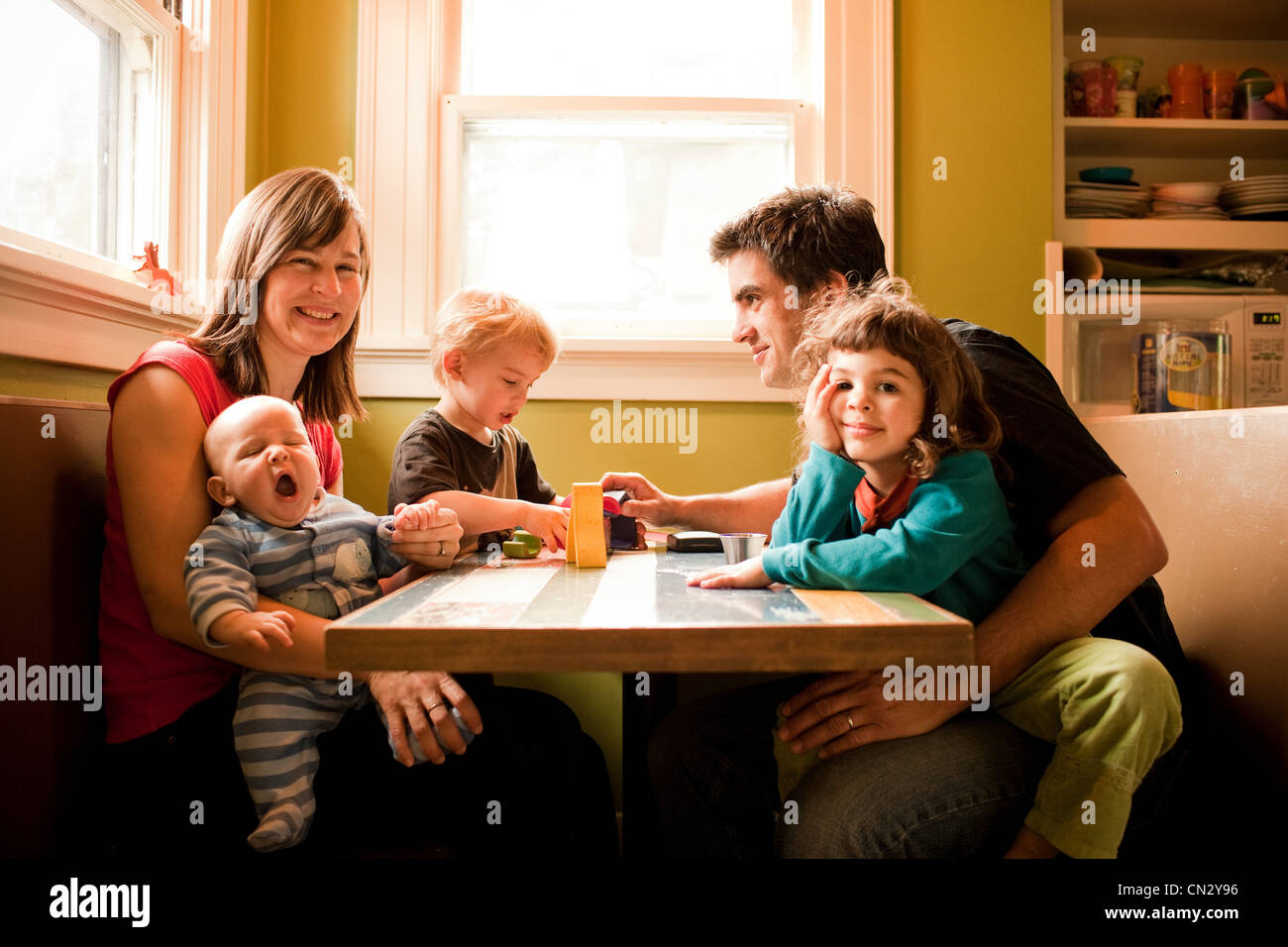 Family sitting at kitchen table Stock Photo - Alamy