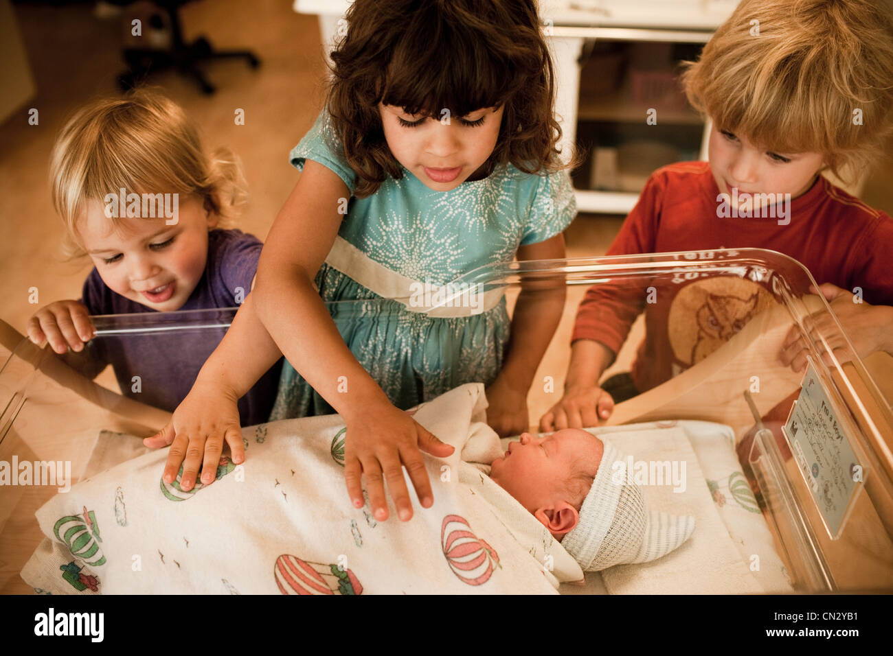 Siblings looking at newborn baby brother in hospital Stock Photo - Alamy
