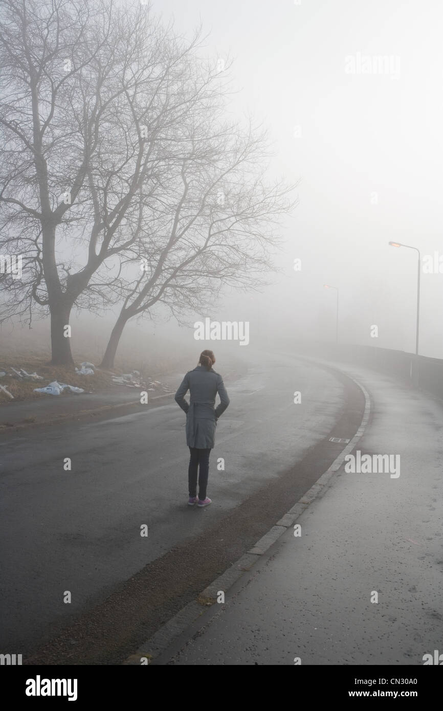 Teenage girl standing in road in the mist Stock Photo - Alamy