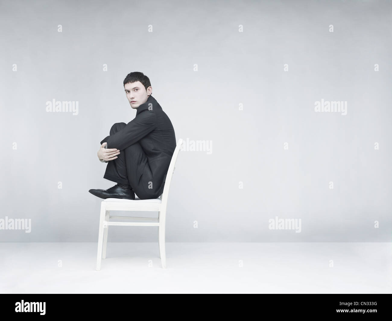 Surreal portrait of a man sitting on a white stool Stock Photo - Alamy