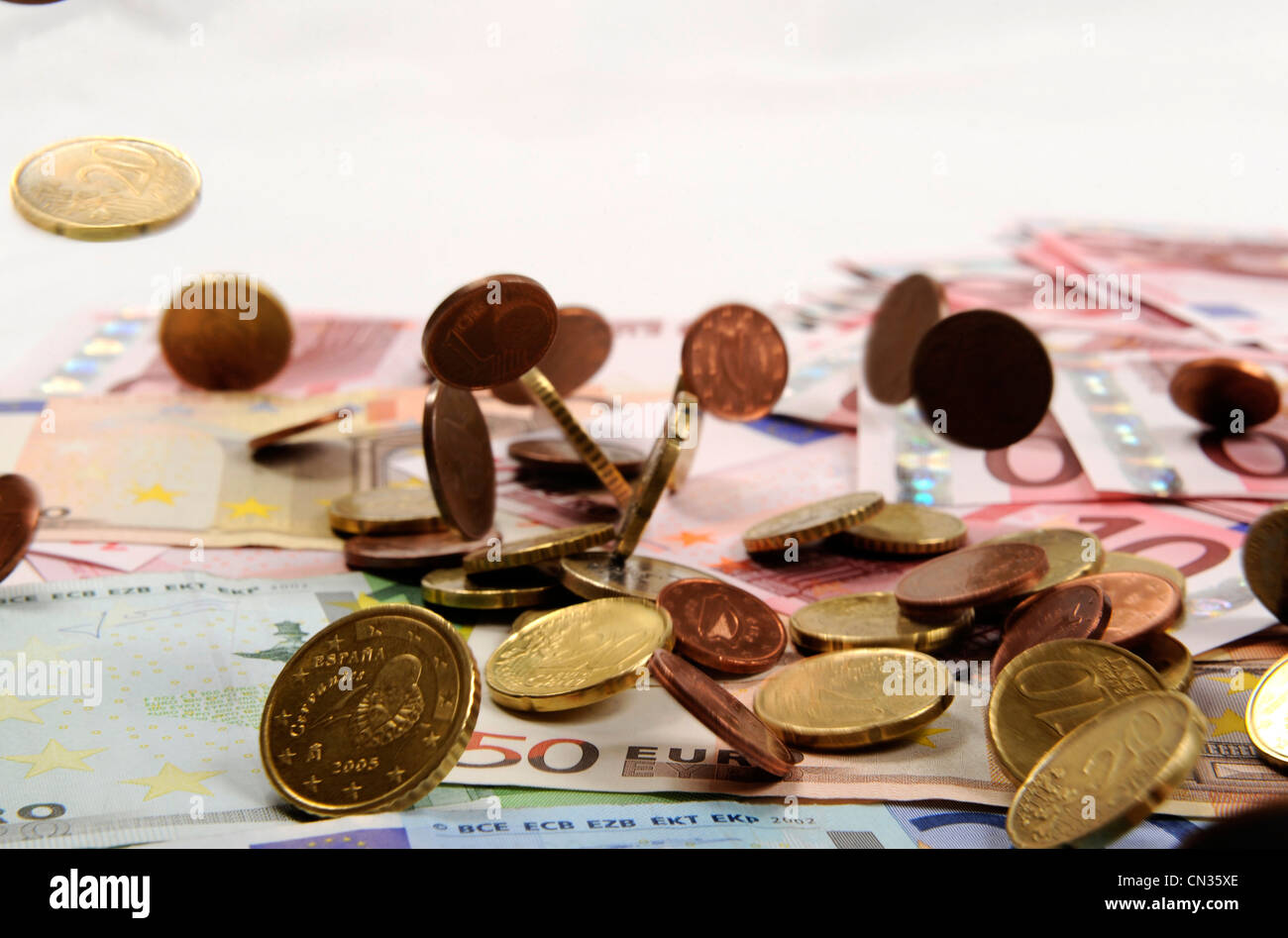 Euro coins falling on euro banknotes, isolated Stock Photo - Alamy