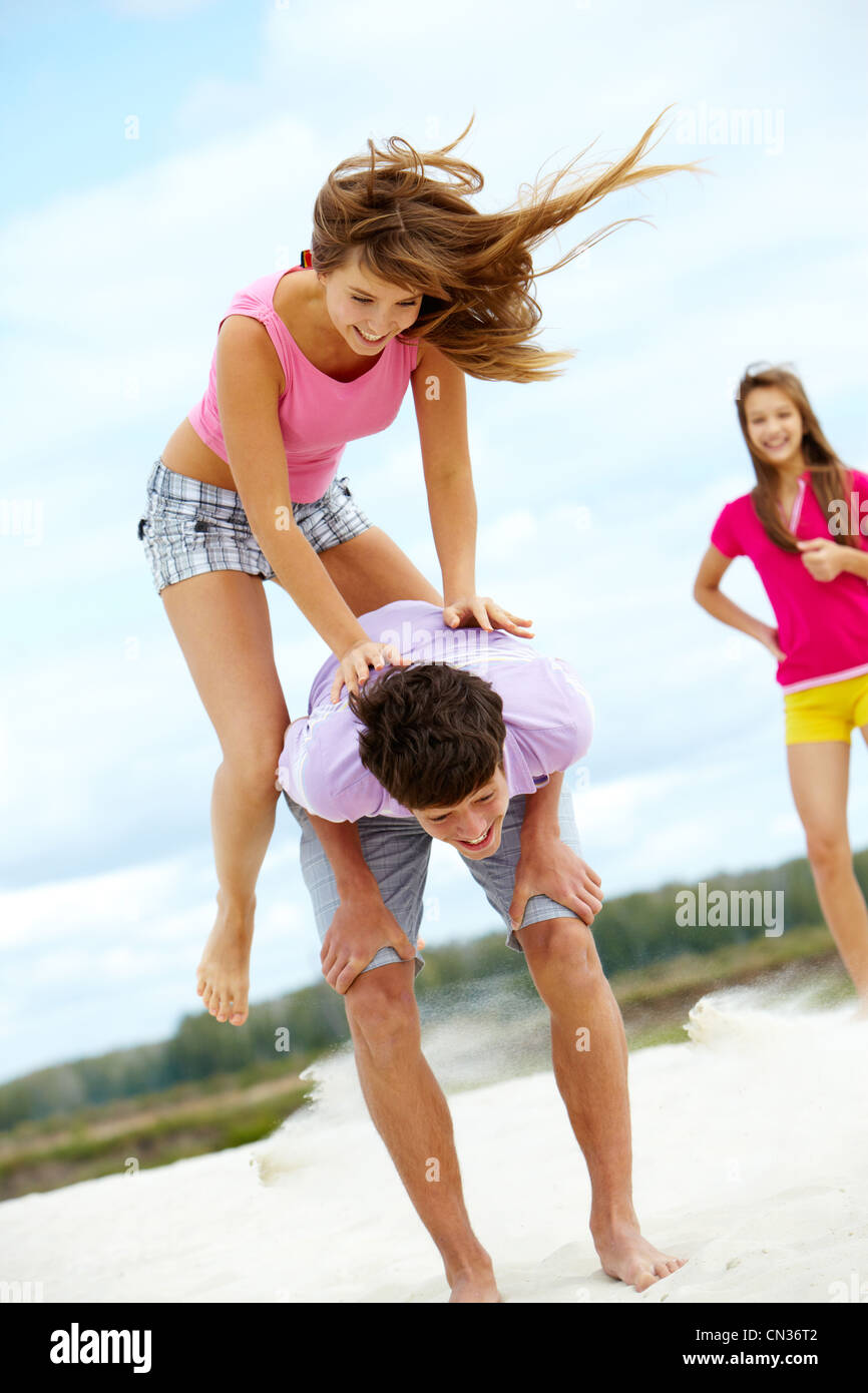 Vertical shot of a girl jumping over her friend’s back, vivid an ...
