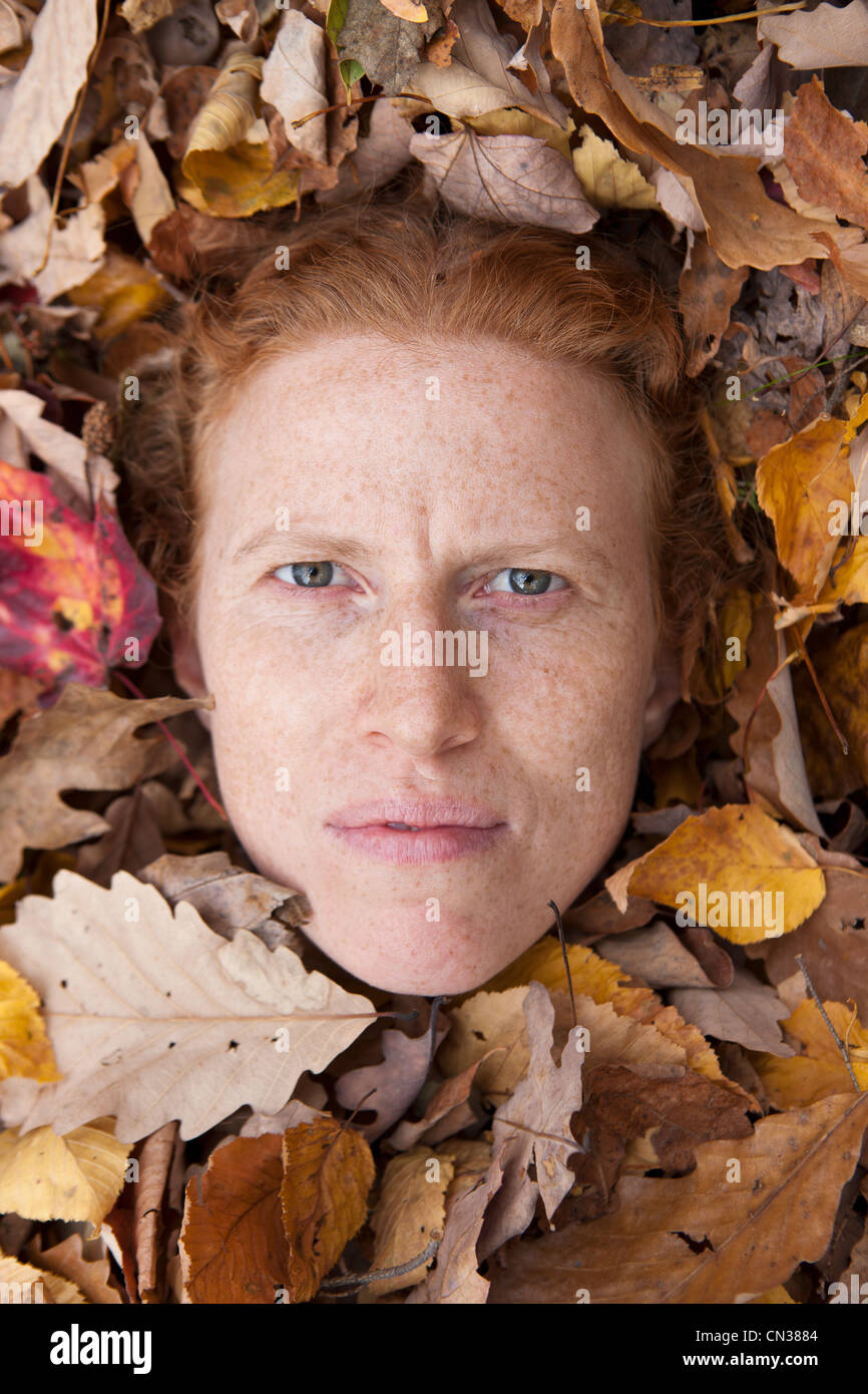 Woman's face peering through autumn leaves Stock Photo - Alamy