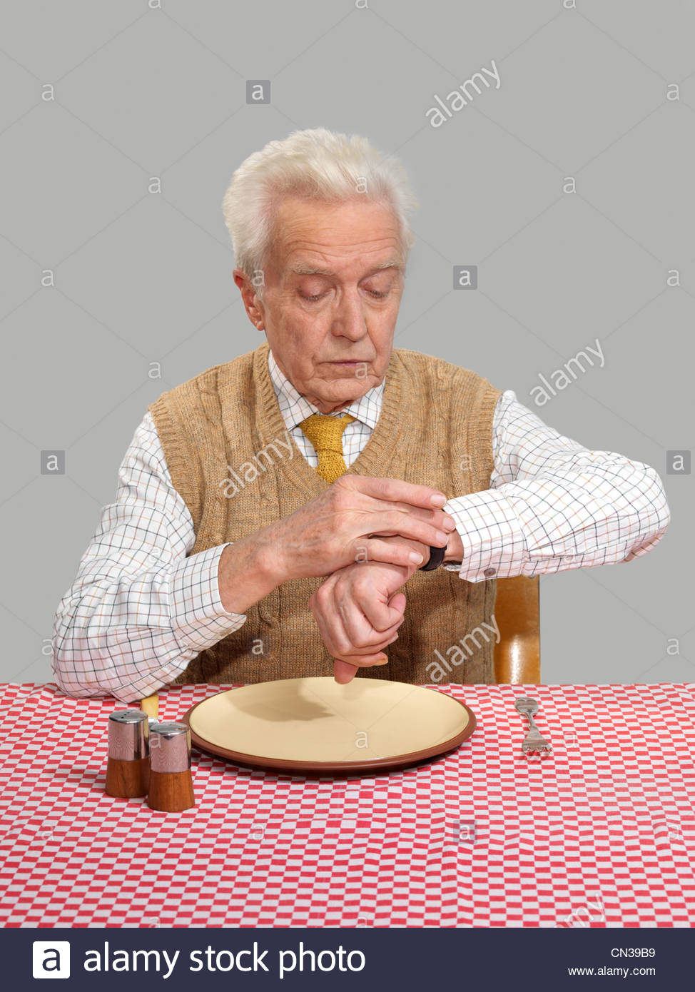 Senior man looking at watch whilst waiting for food Stock Photo ...