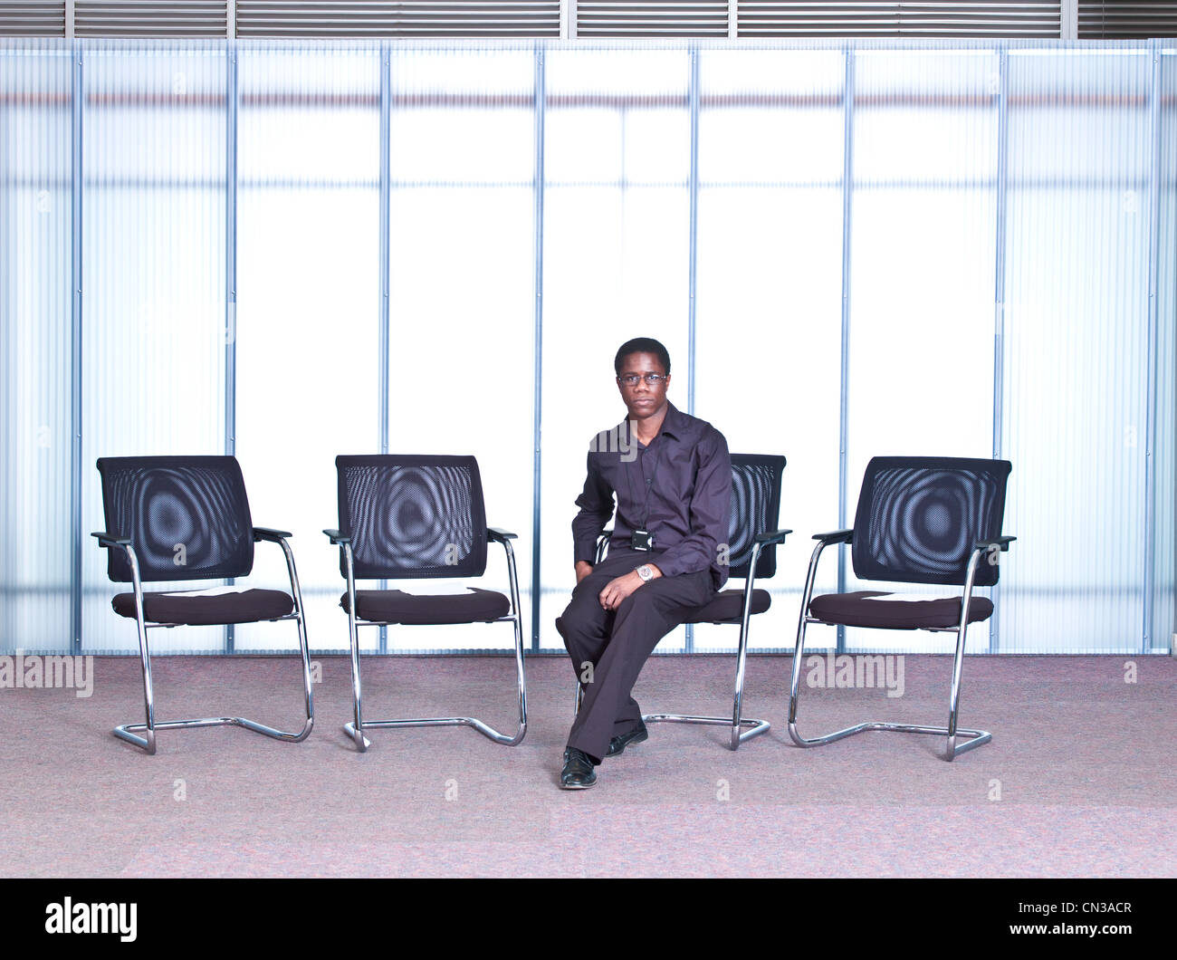 Man sitting on chair in empty office, portrait Stock Photo - Alamy