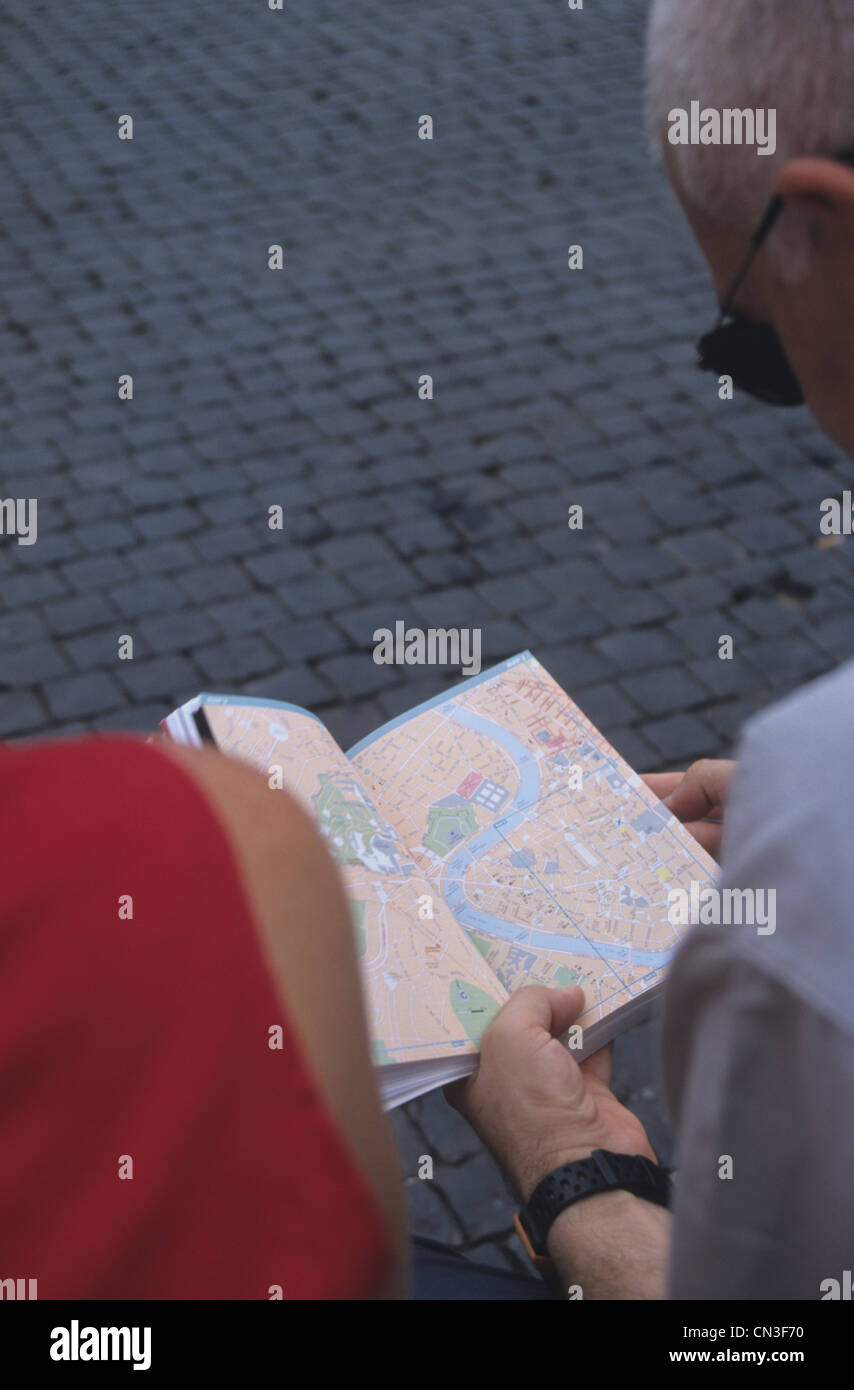 A man looking for directions in his map while taking a break from ...