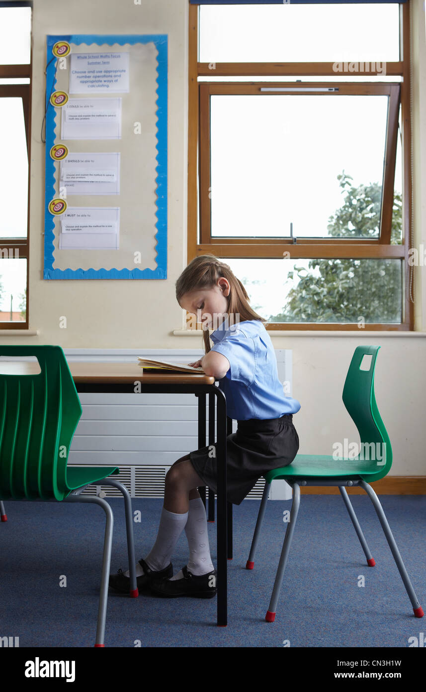 School girl reading a book at a desk in a classroom Stock Photo - Alamy