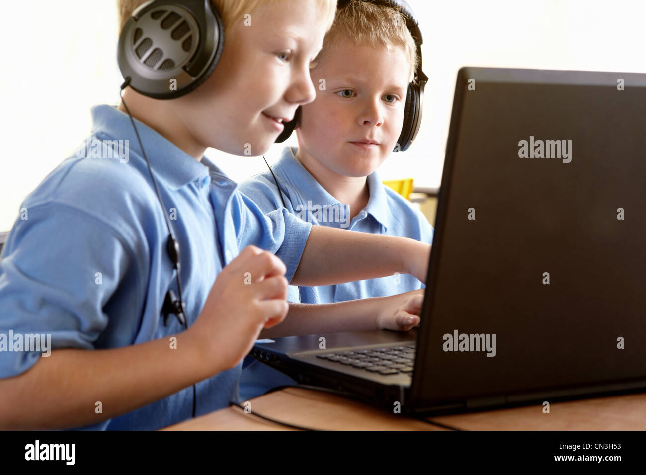 Two school boys wearing headphones, looking at computer screen Stock ...