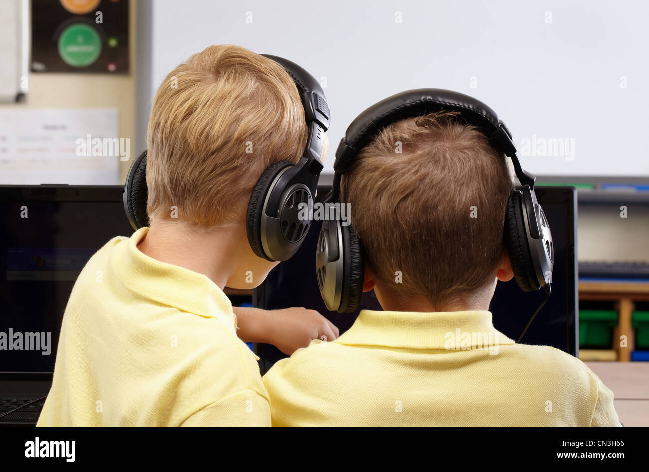 Two school boys wearing headphones, looking at computer screen Stock ...