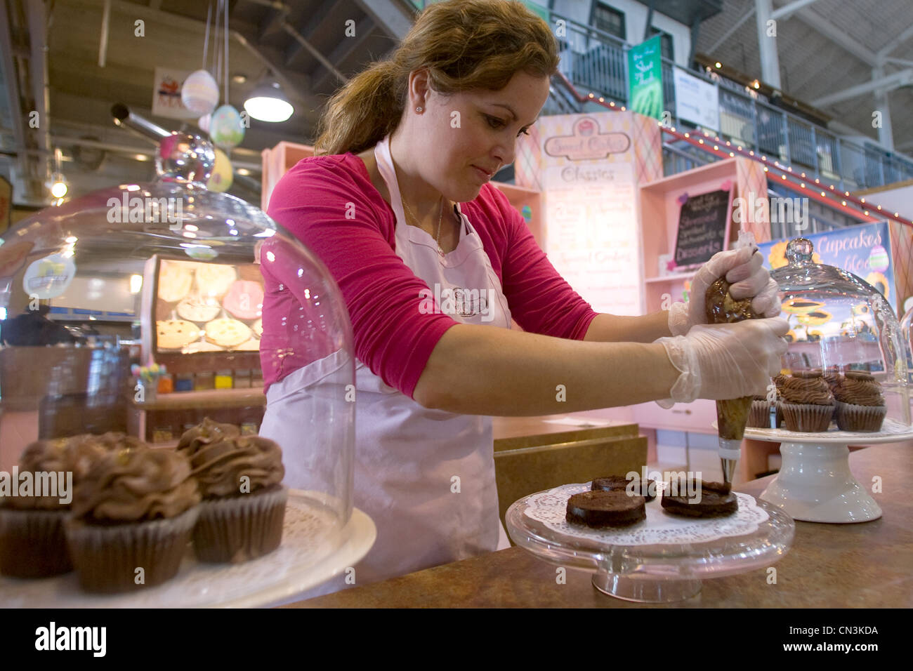 An employee of Sweet Cakes bakery in London decorates chocolate peanut ...