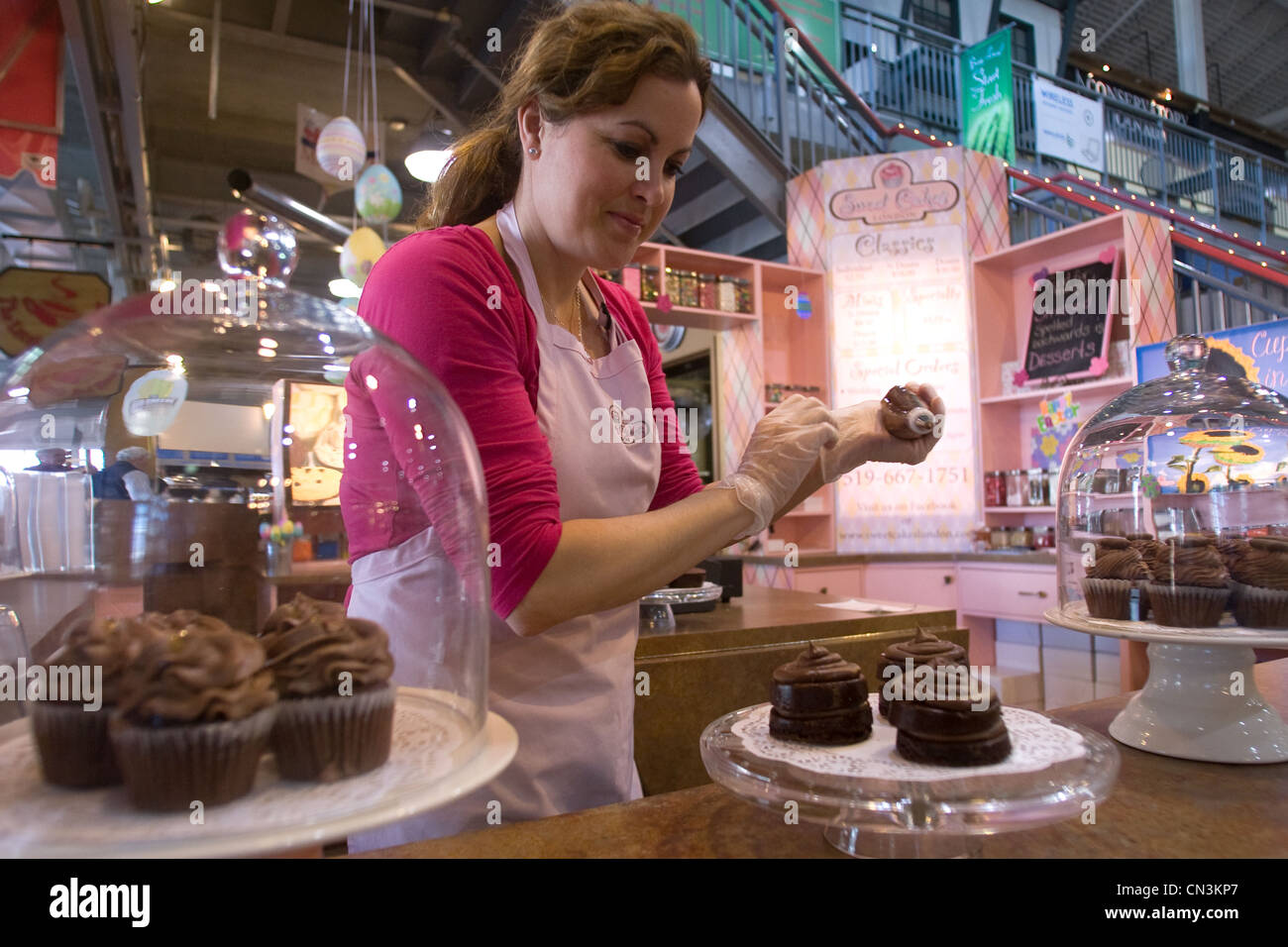 An employee of Sweet Cakes bakery in London decorates chocolate peanut ...