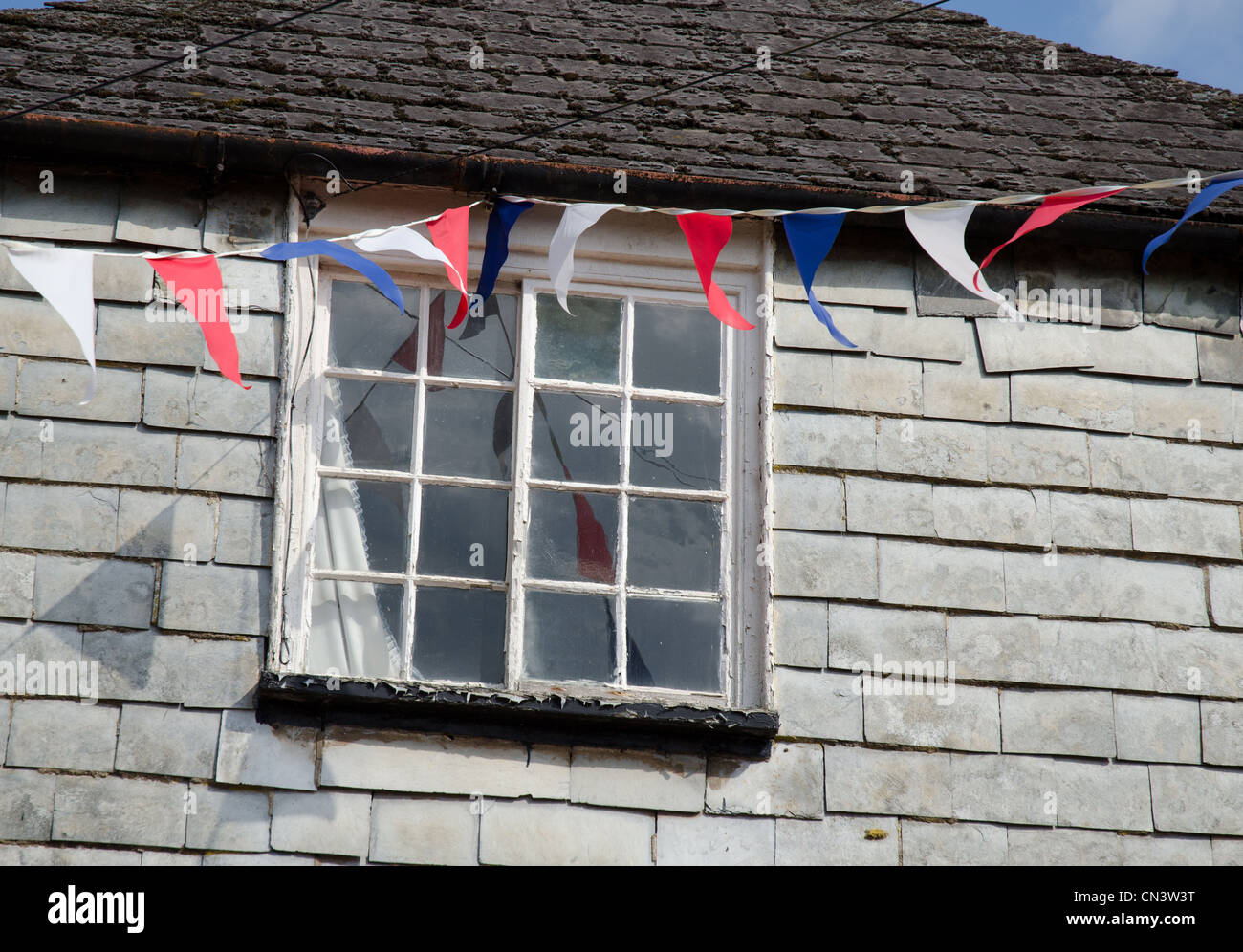 Blue, white and red flags or bunting attached to an old building royal ...