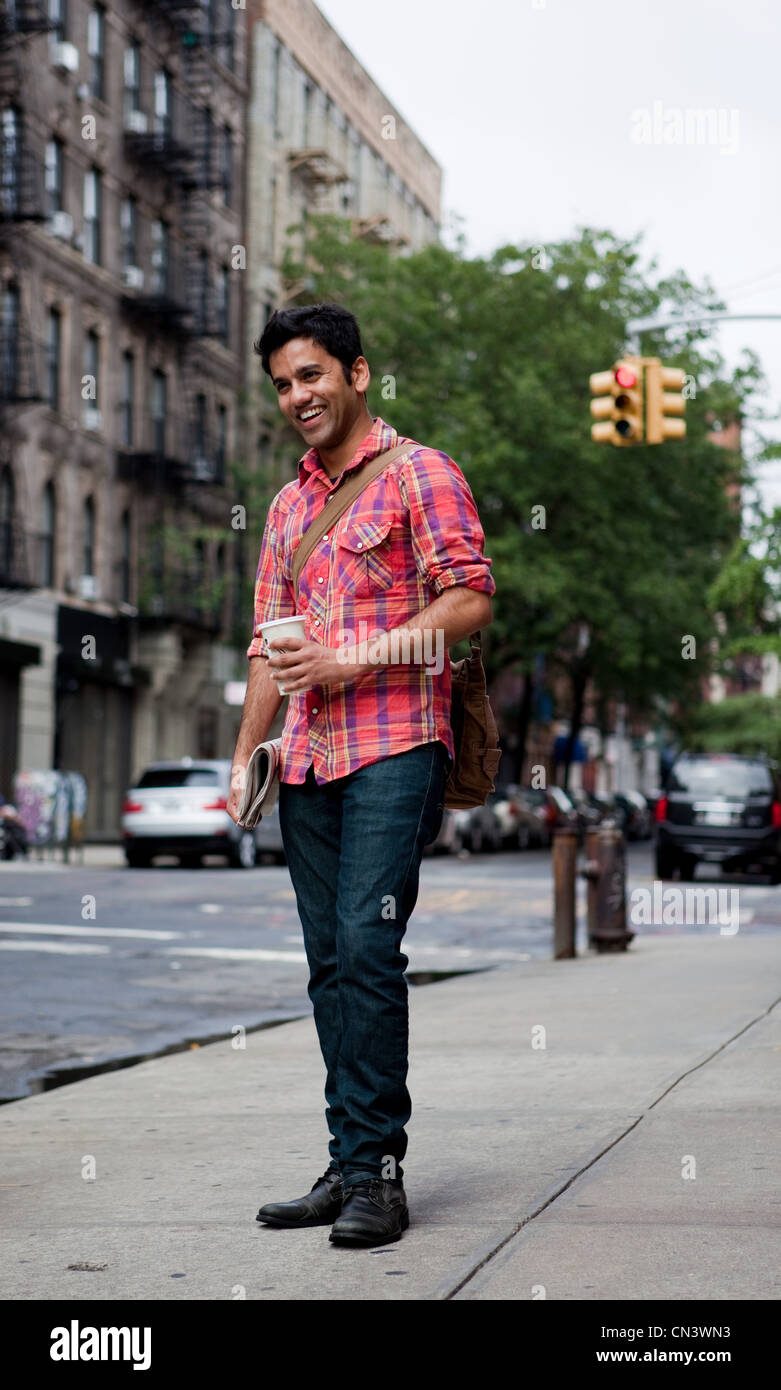 Young man walking along city street, smiling Stock Photo - Alamy Young man walking along city street, smiling Stock Photo - Alamy
