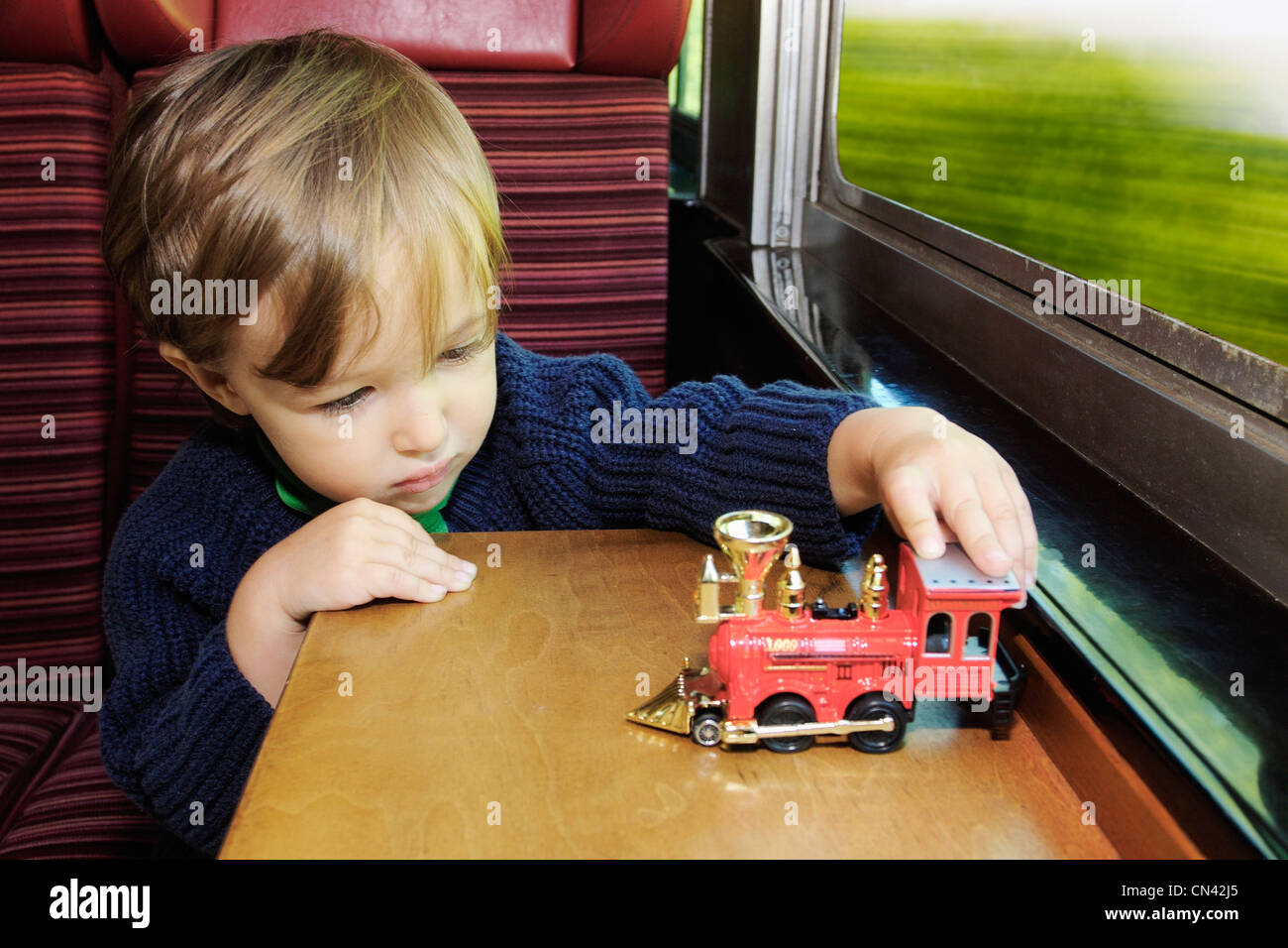 Young Boy Playing with Toy Train while Riding in a Train, between ...