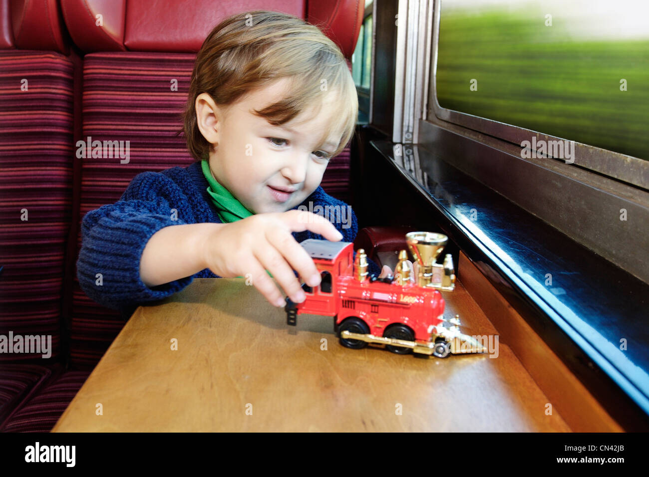 Young Boy Playing with Toy Train while Riding in a Train, between ...