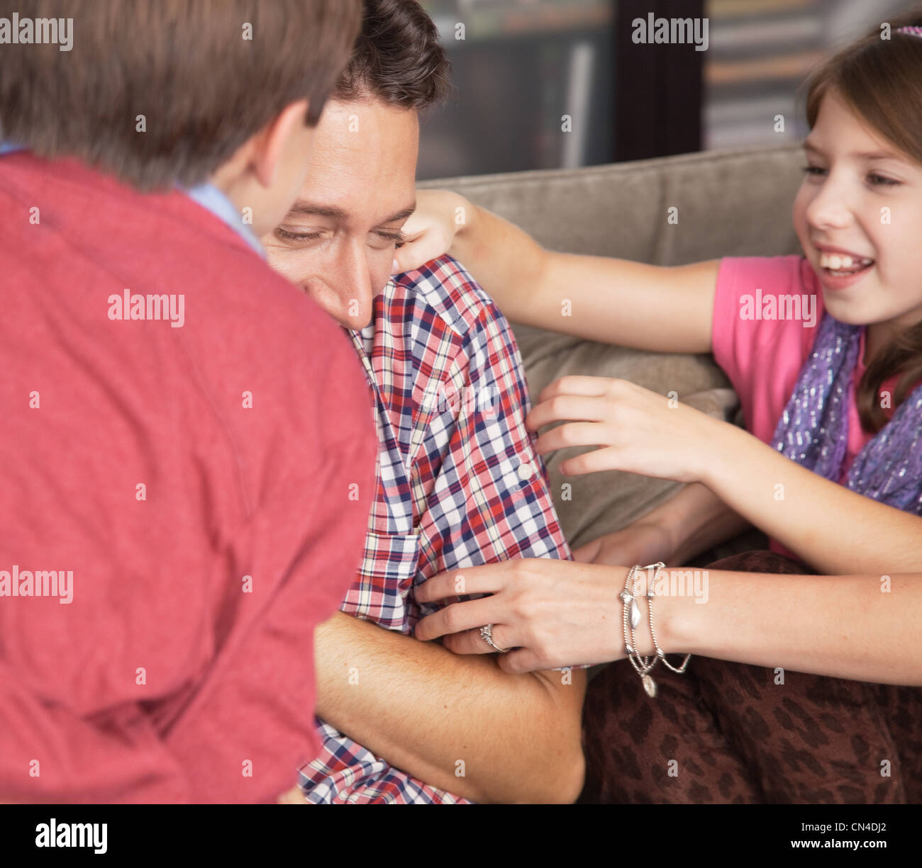 Children tickling father on sofa hi-res stock photography and images ...