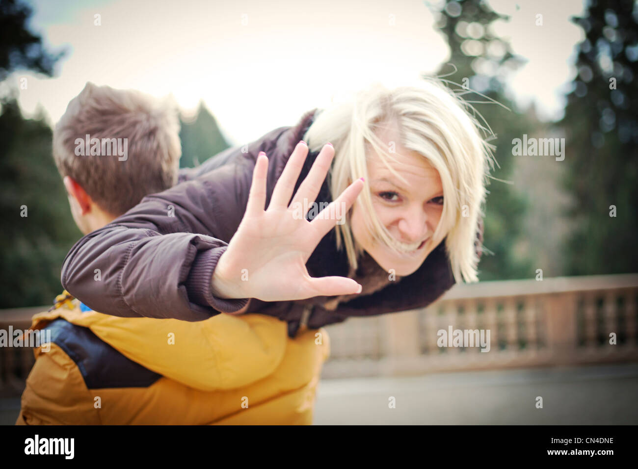 Blonde woman playfully reaching out to the camera while being carried ...