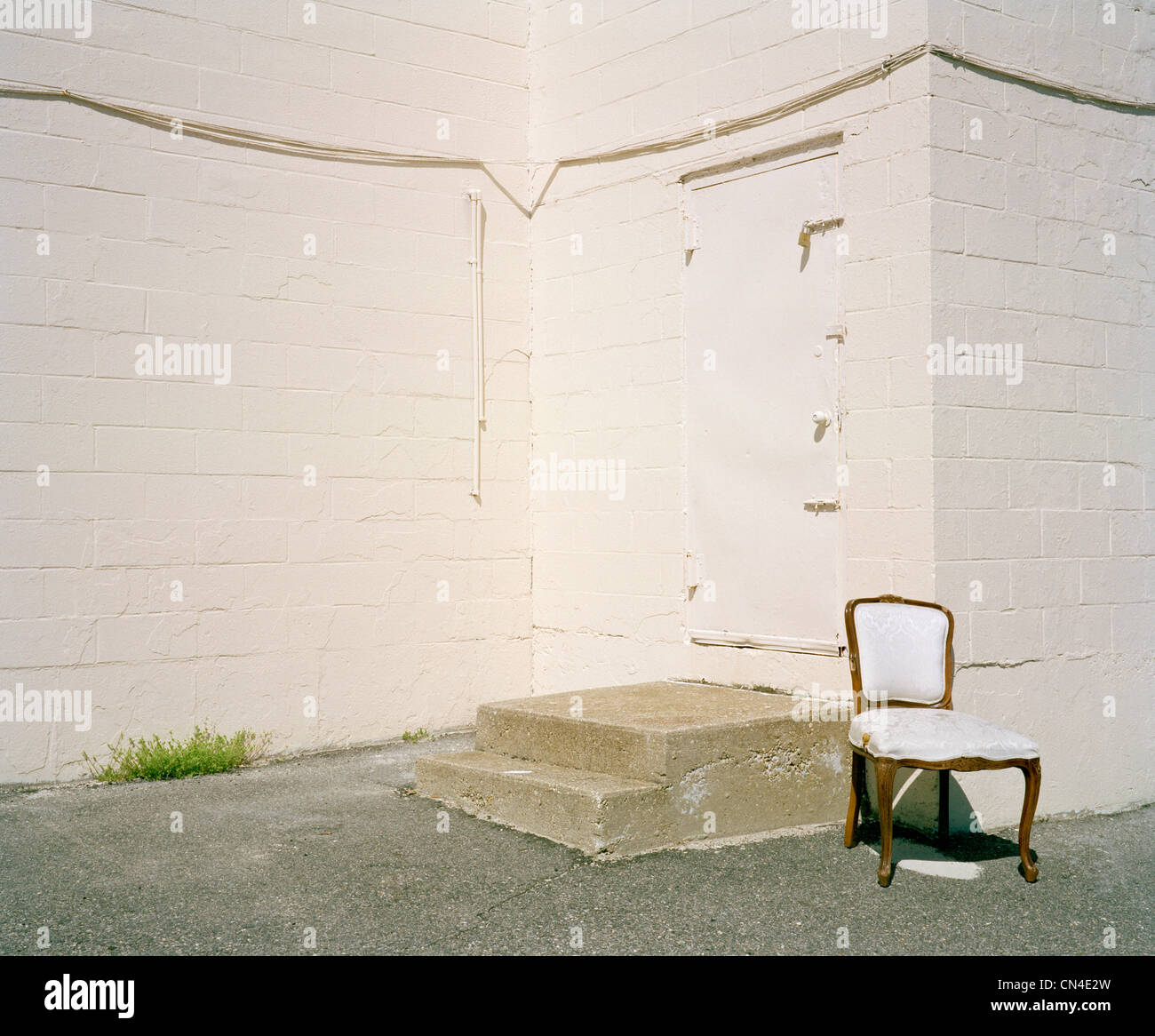 Empty chair outside closed door of building Stock Photo - Alamy