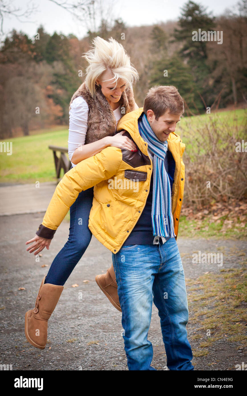 Woman piggybacking on her boyfriend. Cold weather, photographed outside ...