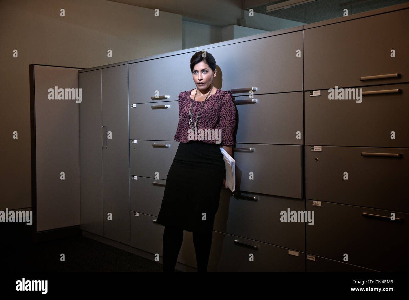Office worker holding file behind back by filing cabinets Stock Photo ...