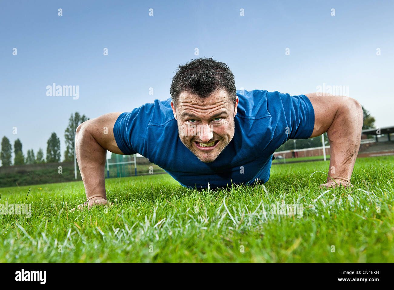 Mid adult man performing press ups on pitch Stock Photo - Alamy