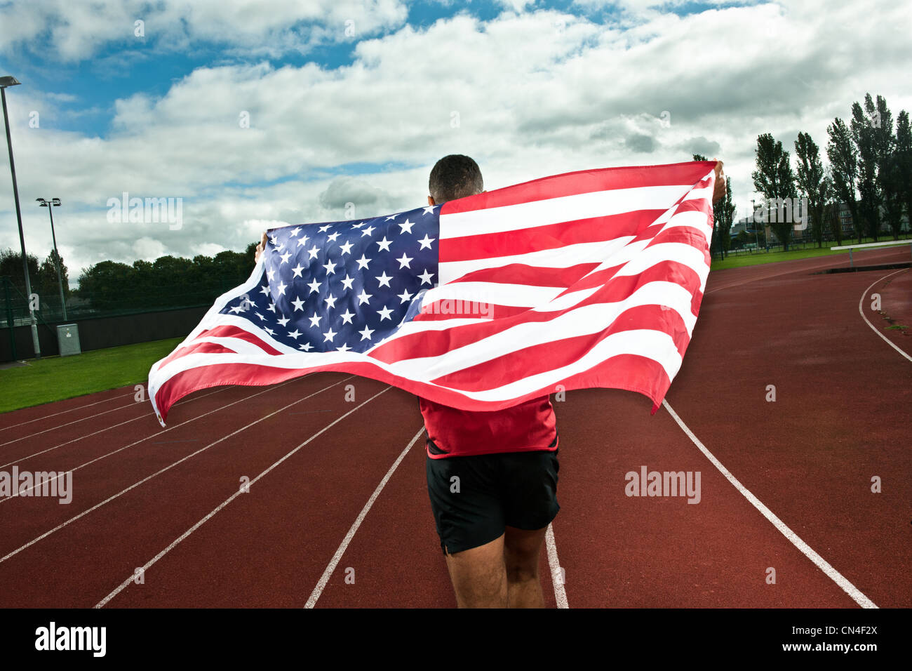 Sprinter running with US flag on sportstrack Stock Photo - Alamy