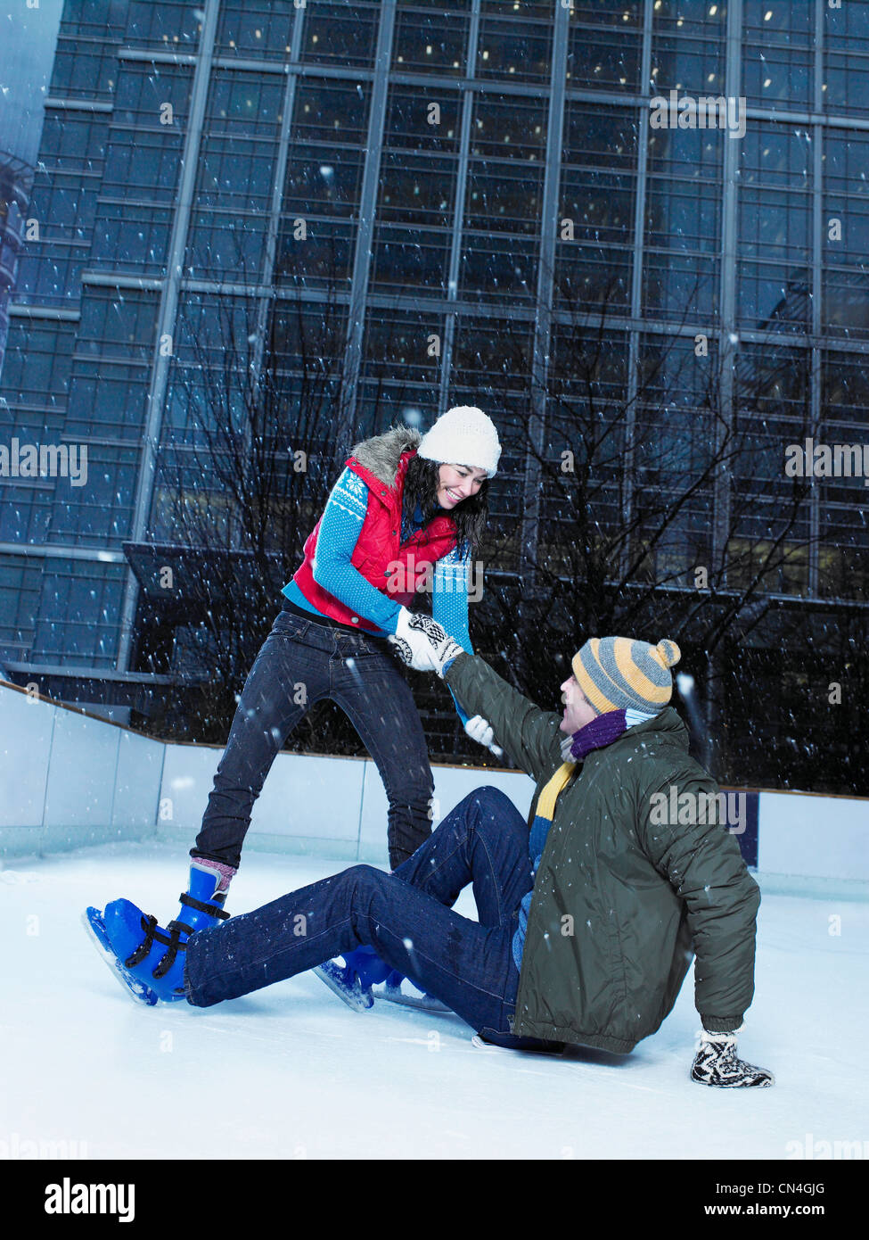 Woman helping man up from ice rink Stock Photo - Alamy