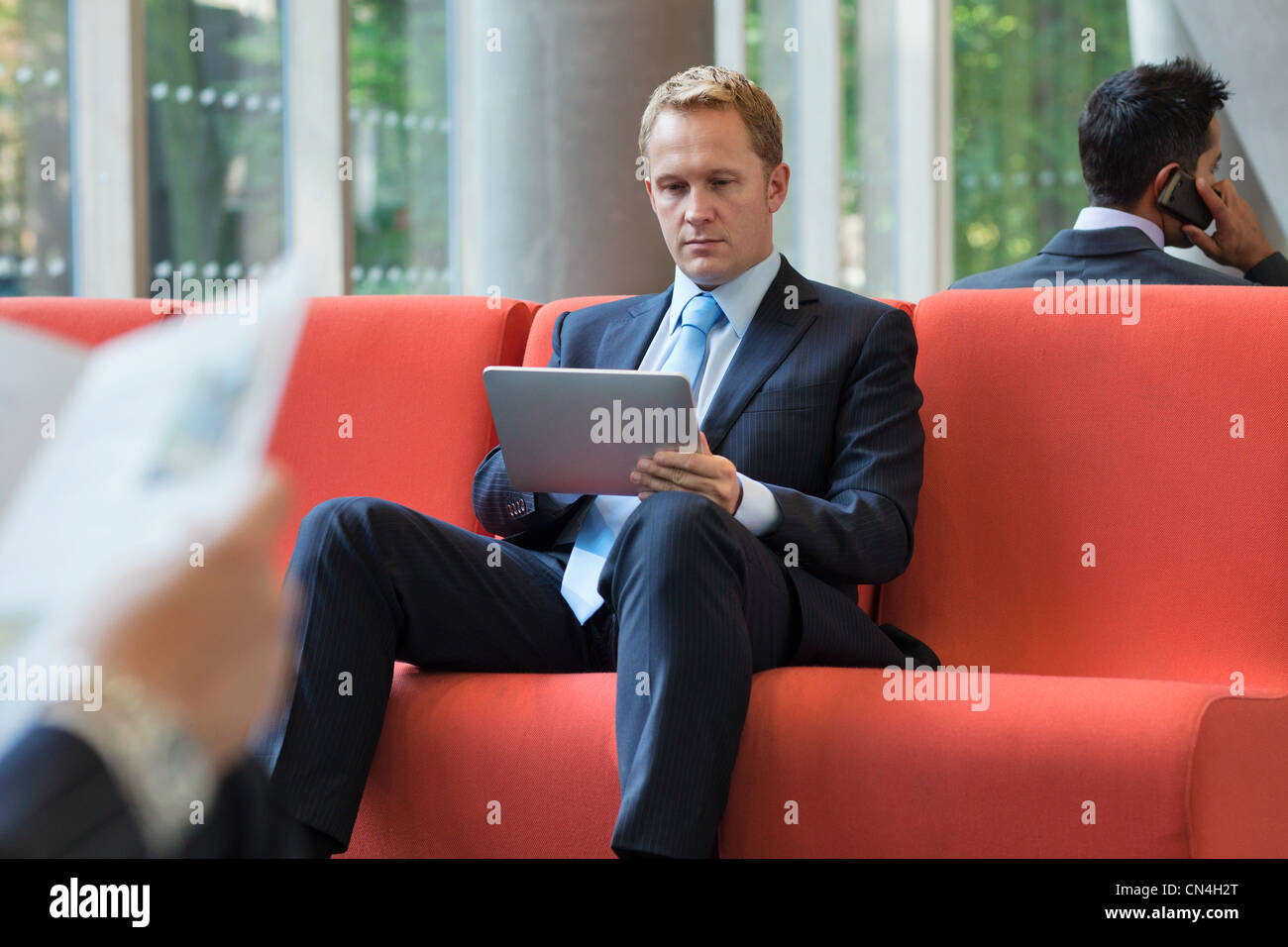 Businessman using digital tablet in office lobby Stock Photo - Alamy