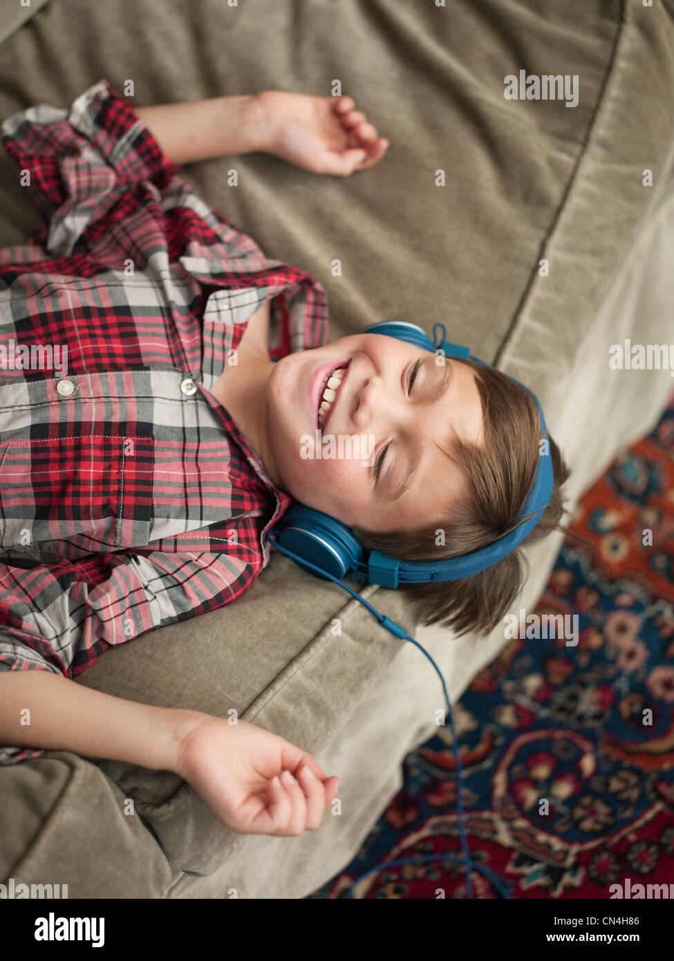 Boy relaxing on sofa and wearing headphones Stock Photo - Alamy