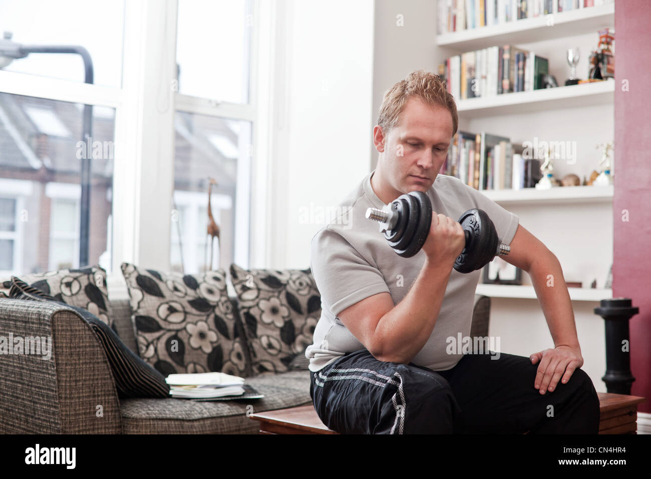 Mid adult man lifting dumb bell in home Stock Photo - Alamy