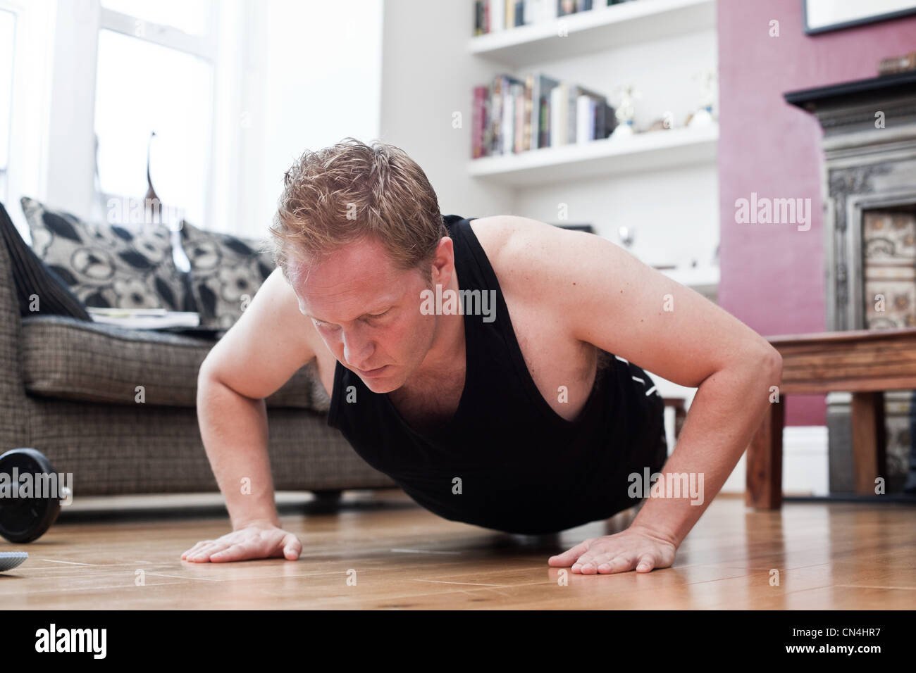 Mid adult man performing press ups at home Stock Photo - Alamy