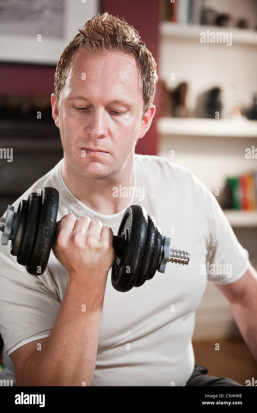 Mid adult man lifting dumb bell in home Stock Photo - Alamy