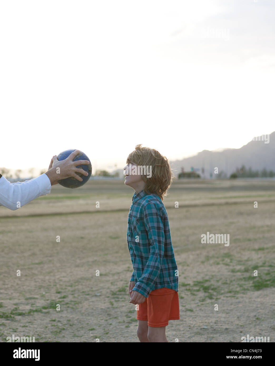 Boy and person holding soccer ball Stock Photo - Alamy