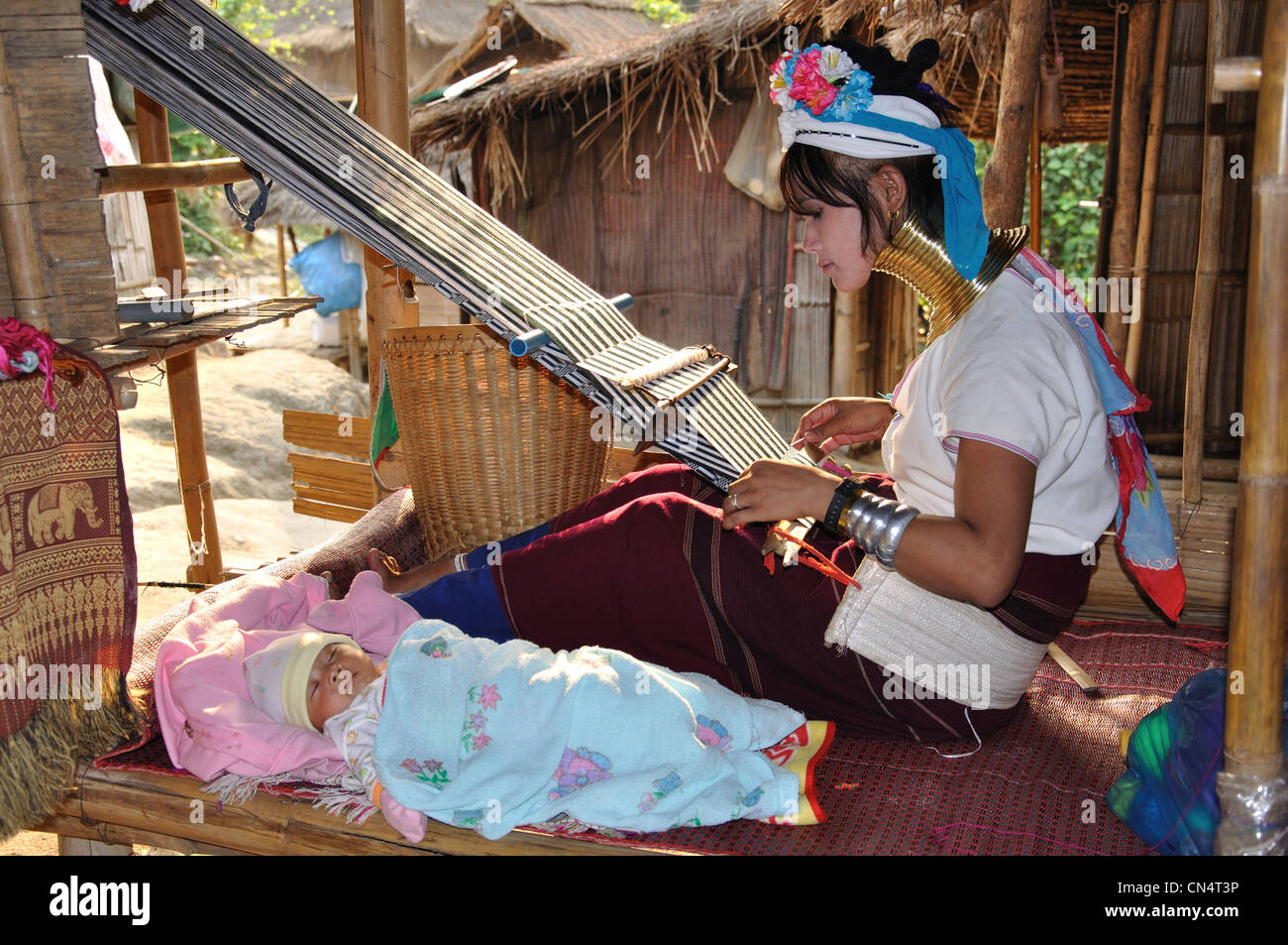 A young Kayan Lahwi girl weaving at Karen Long Neck hill tribe village ...