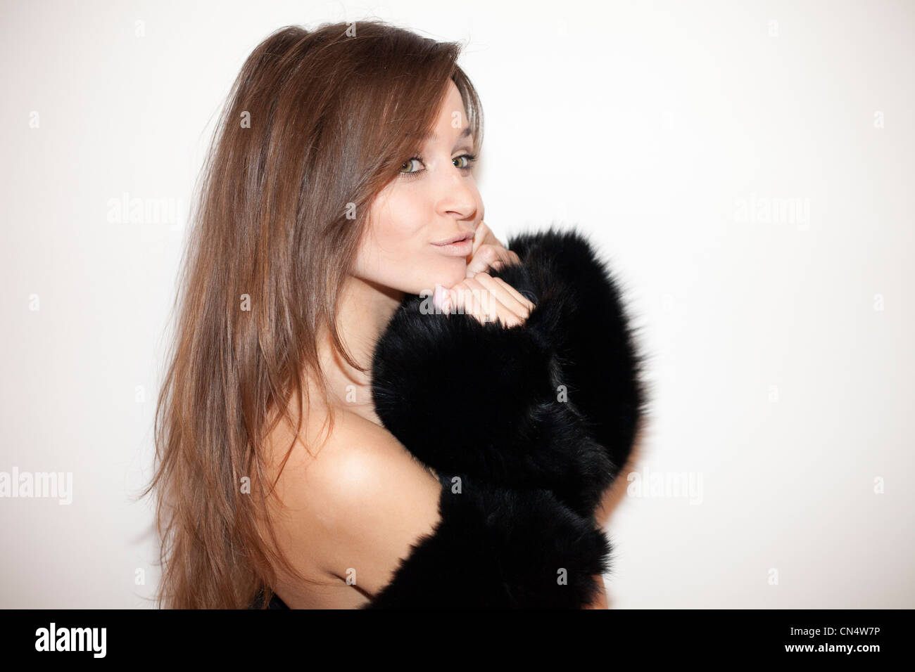 Young female covering herself with fur scarf. Beautiful brunette female ...