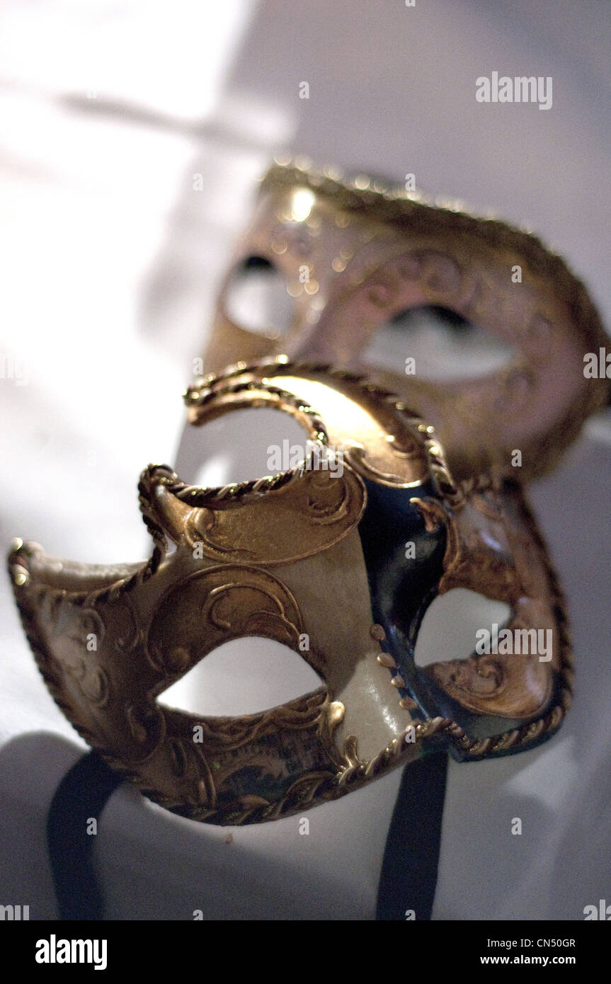 Two gold and black carnival masks on a white tablecloth Stock Photo - Alamy