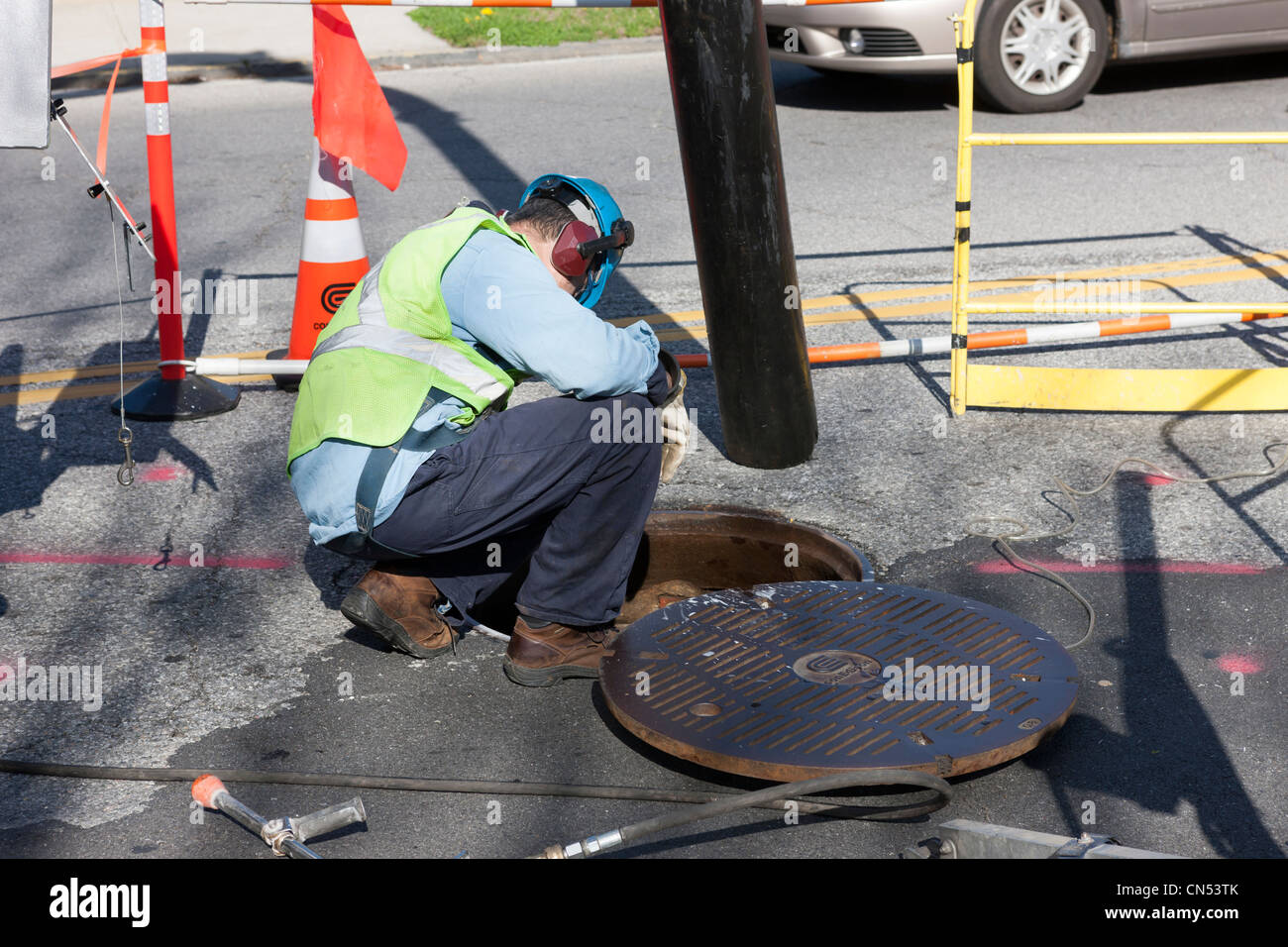 A Con Edison crew member works by a manhole on a street in White Plains ...