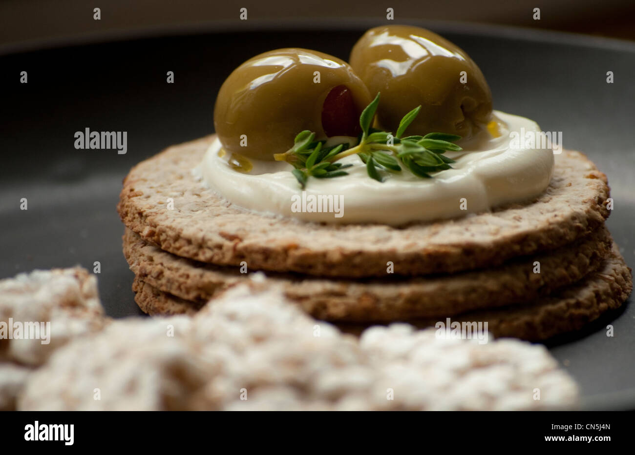 Green olives and mustard on an oatcake Stock Photo - Alamy