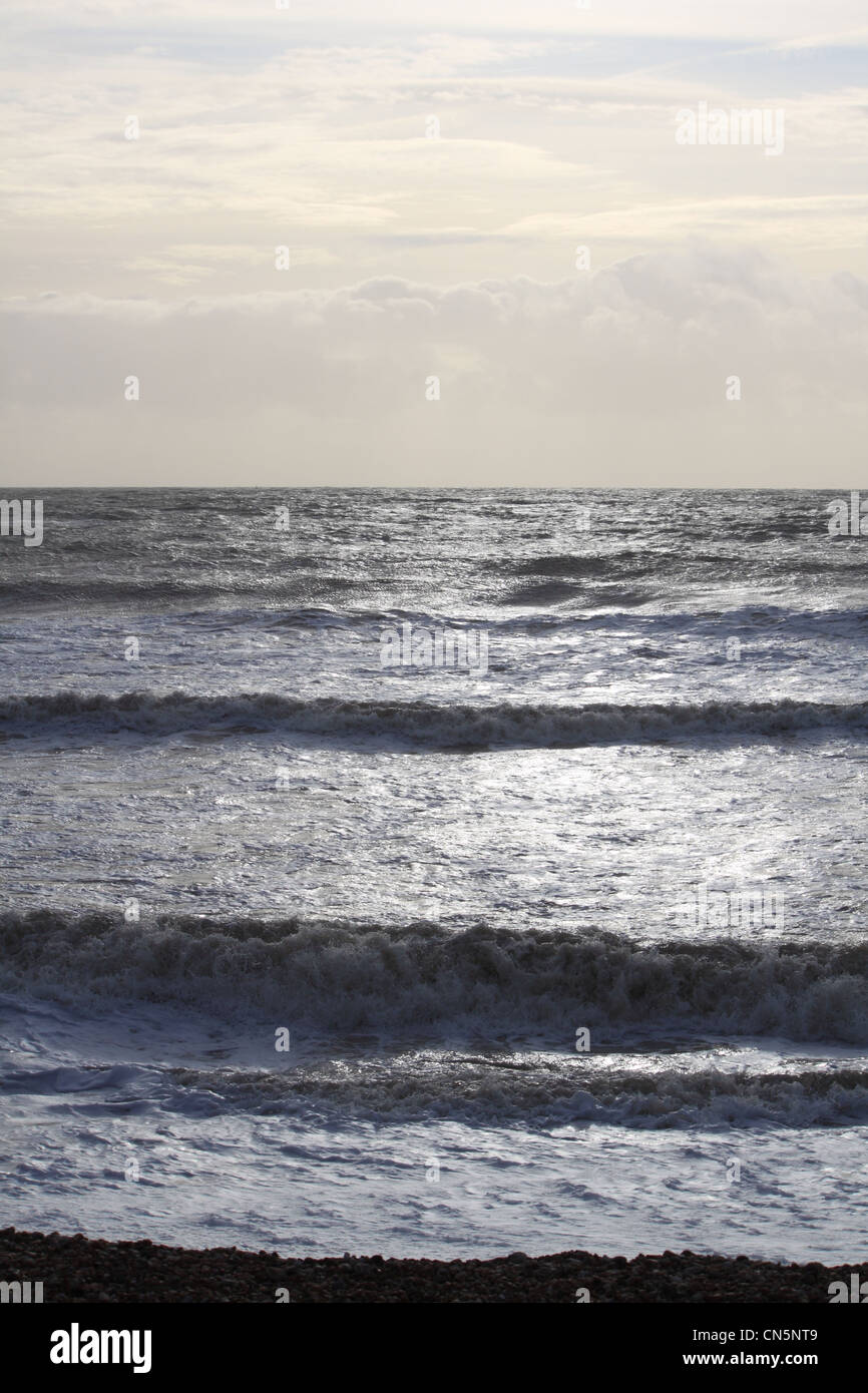 Moody, windswept, rushing sea and cloudy sky with sun breaking through ...