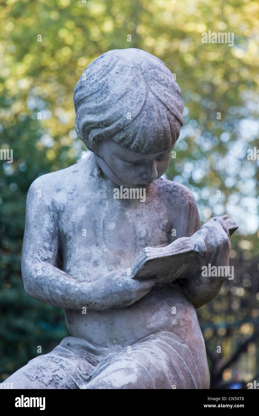Charming statue of little girl reading a book in public square in ...