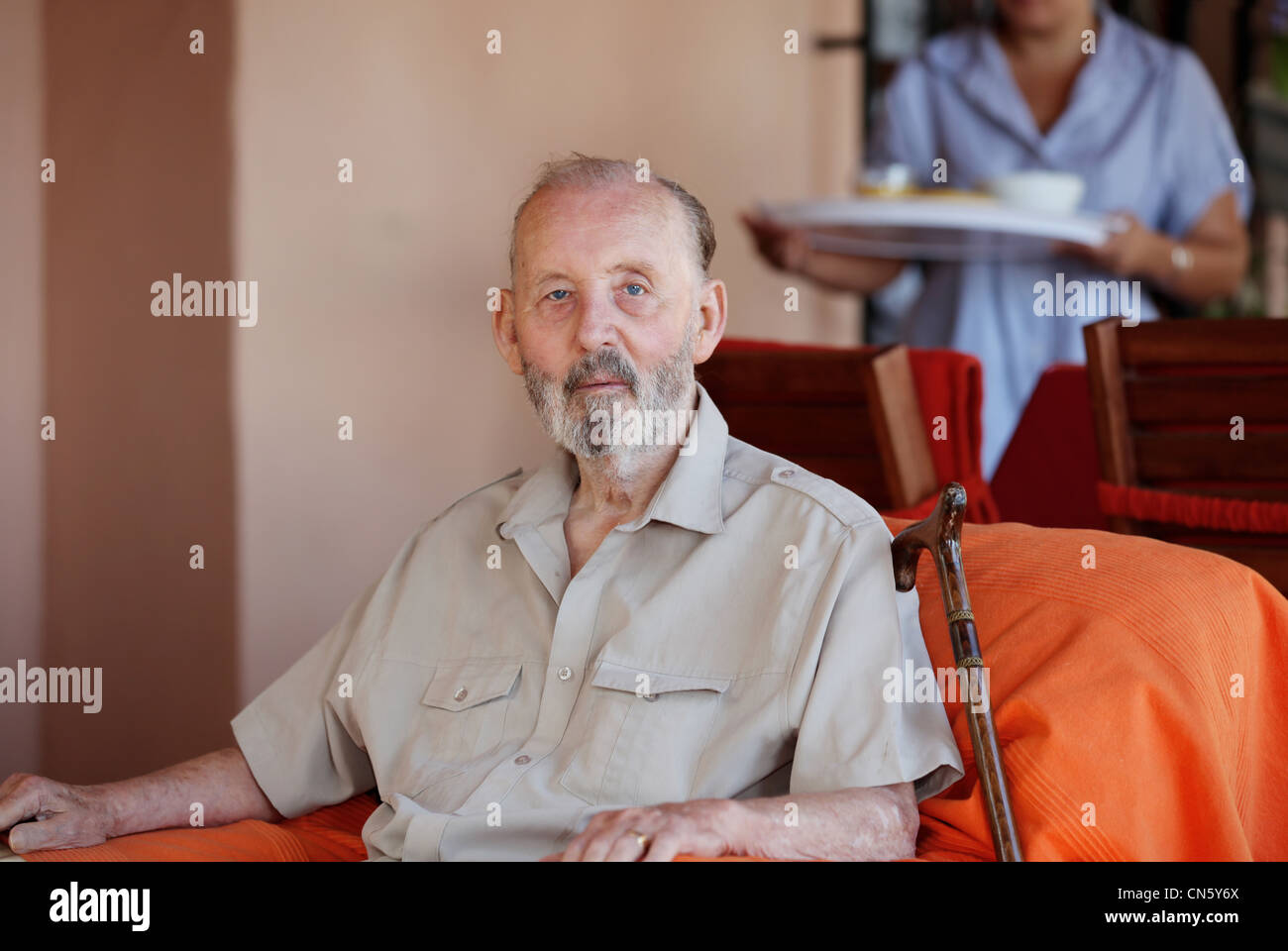 elderly senior man with home help or carer in residential home bringing ...