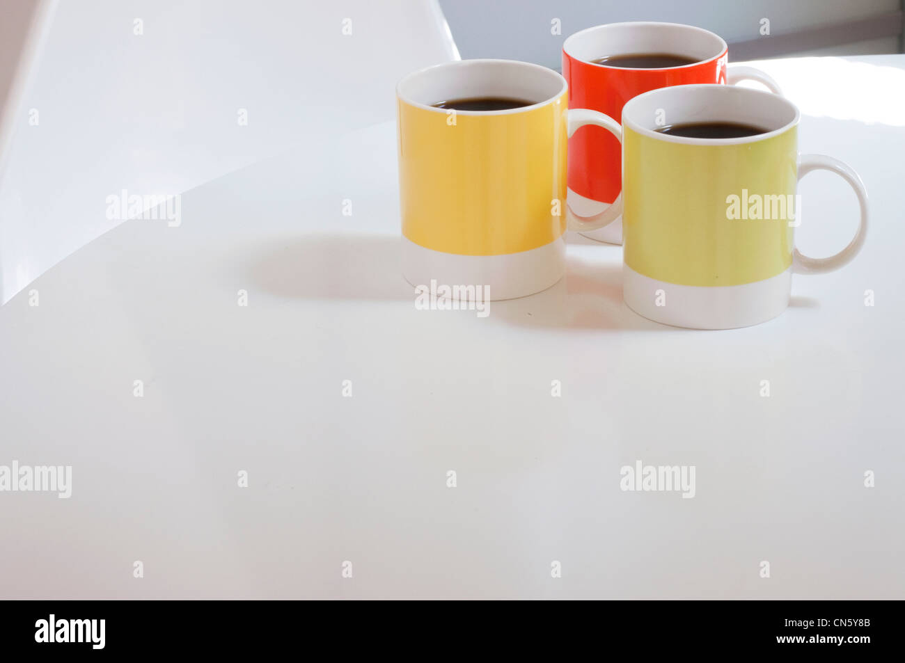 Three mugs of coffee on a white table Stock Photo - Alamy