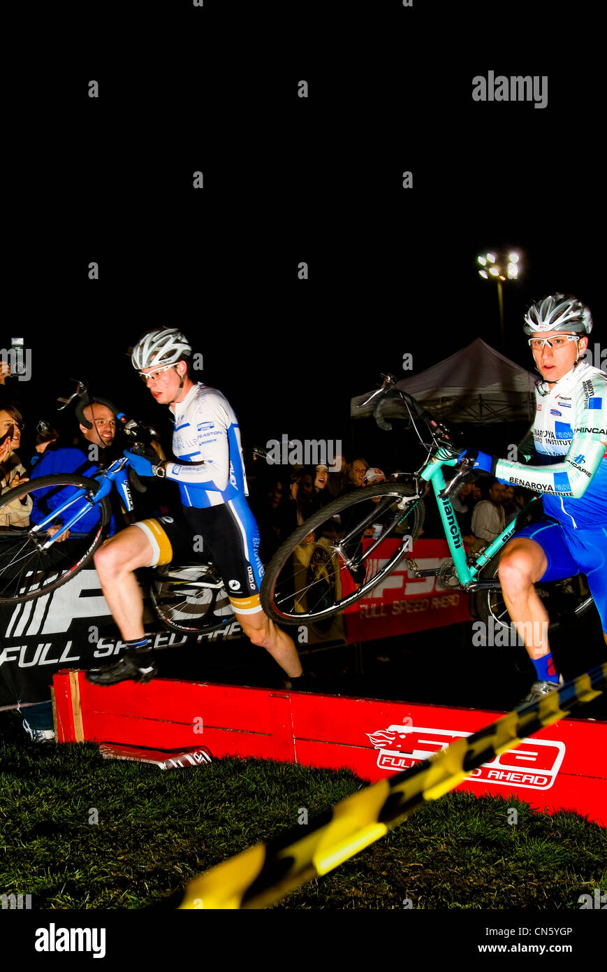 Cyclocross racers jumping over barriers Stock Photo - Alamy