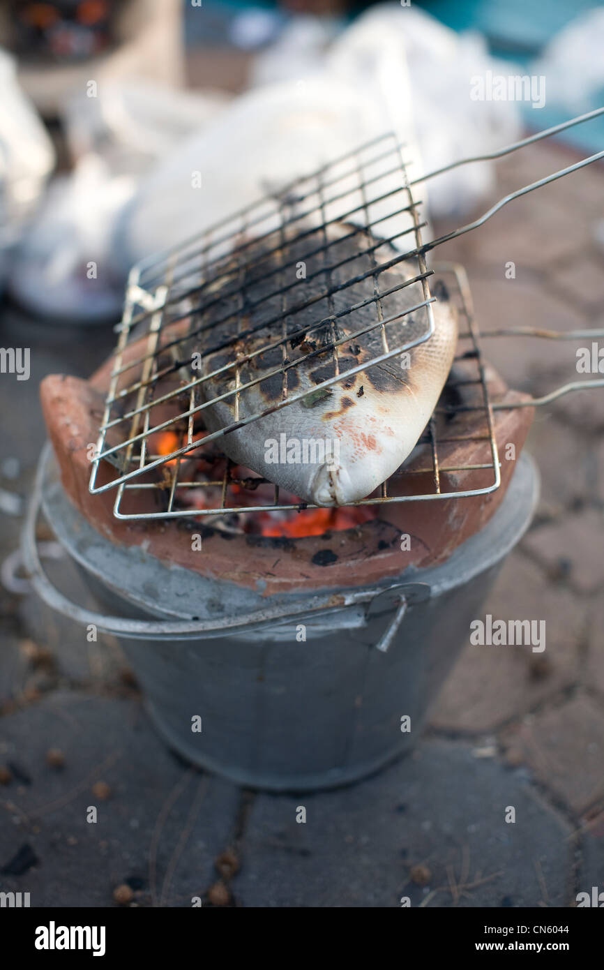 A fish being cooked for a family supper on the promenade by the ...