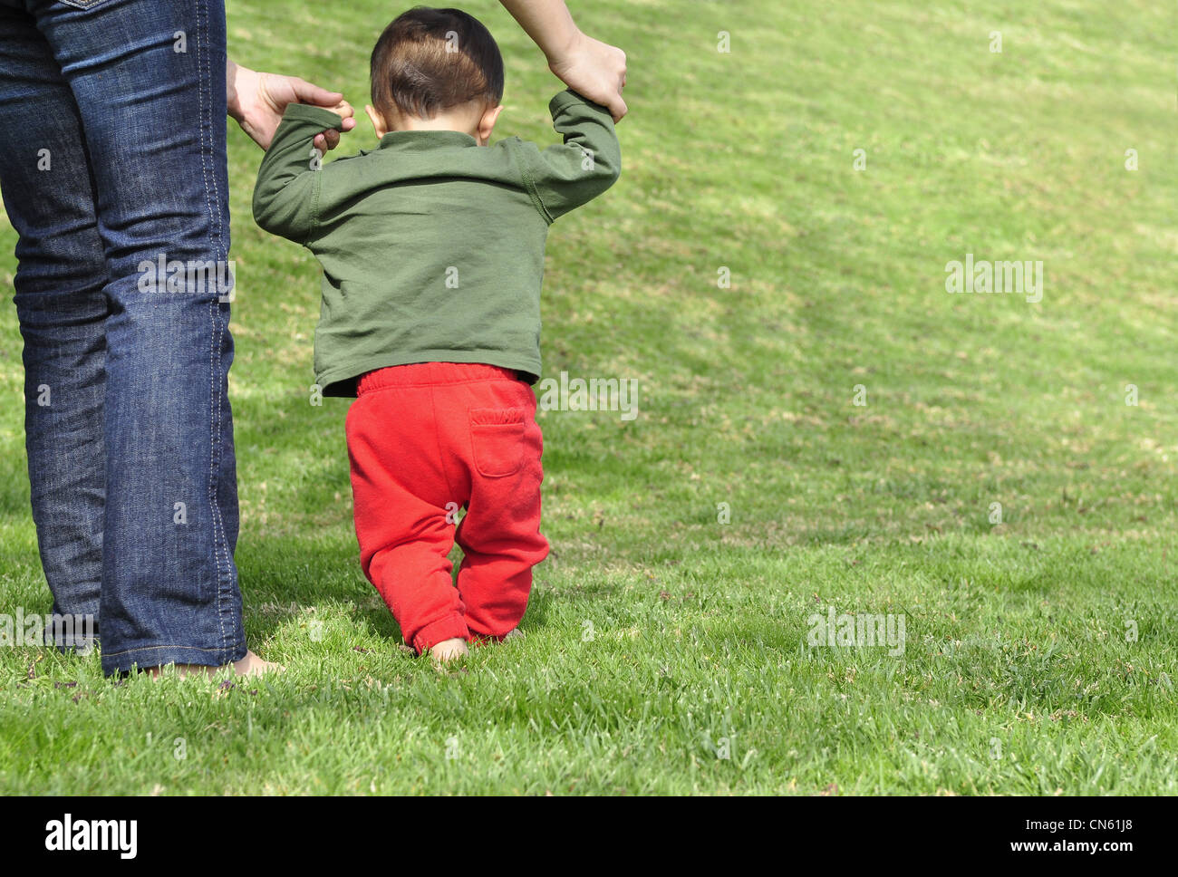 Baby making first steps with the help of his mom Stock Photo - Alamy