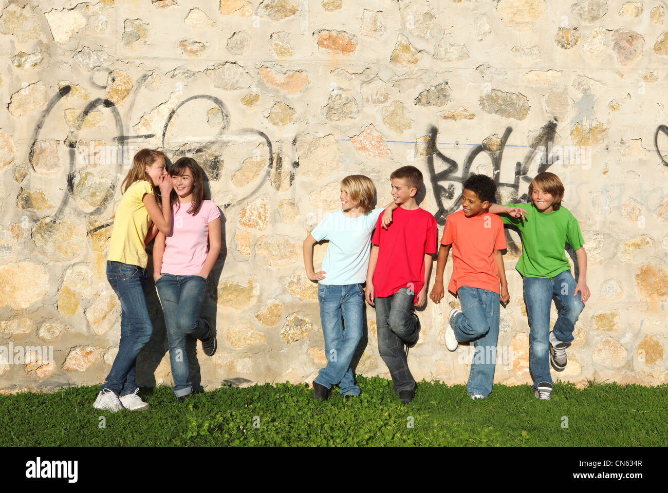 group of diverse teens hanging around out doors whispering secrets and ...