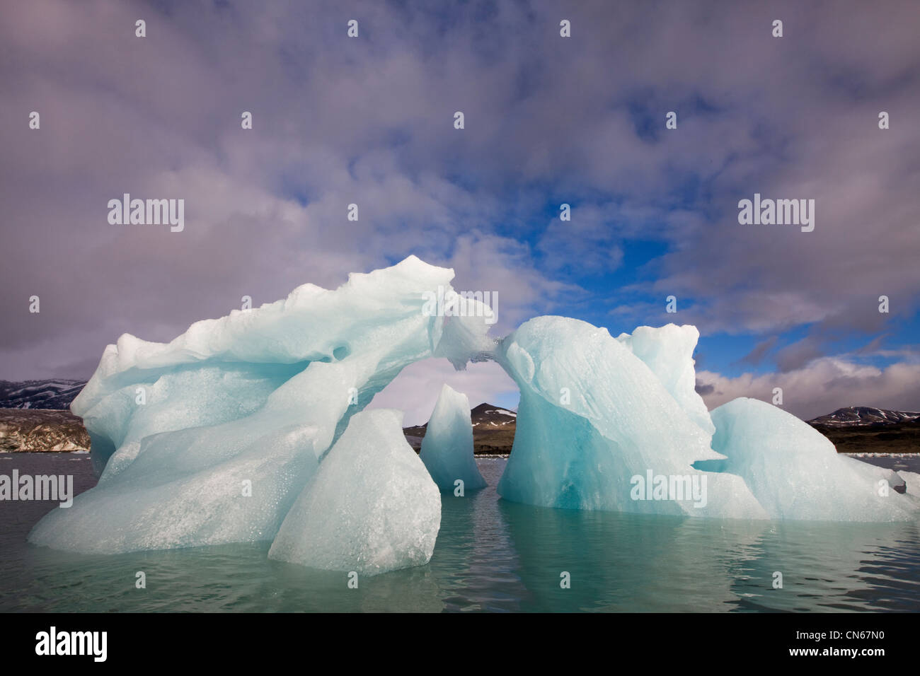 Norway Svalbard Spitsbergen Island Morning sun lights arched iceberg ...