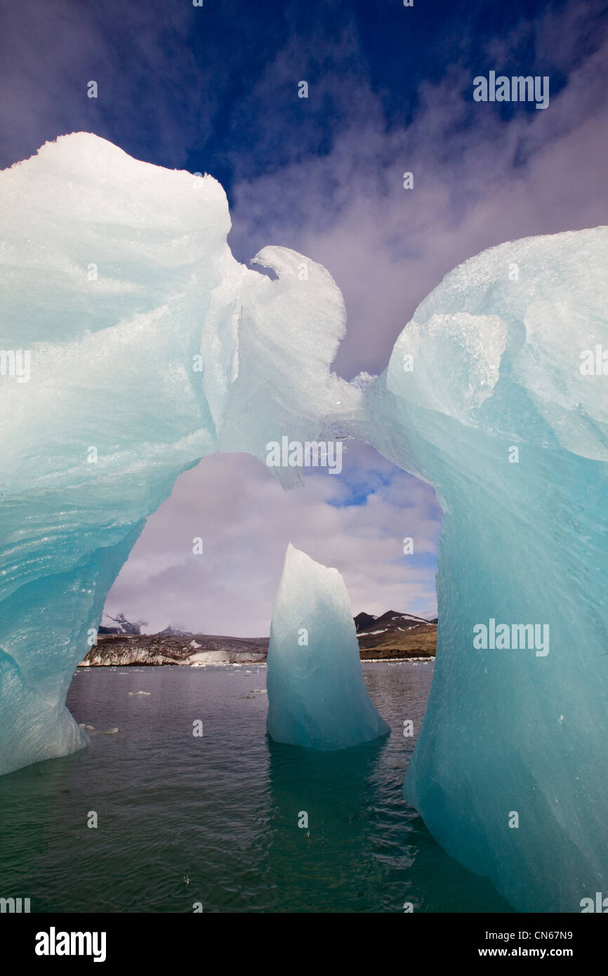 Norway Svalbard Spitsbergen Island Morning sun lights arched iceberg ...