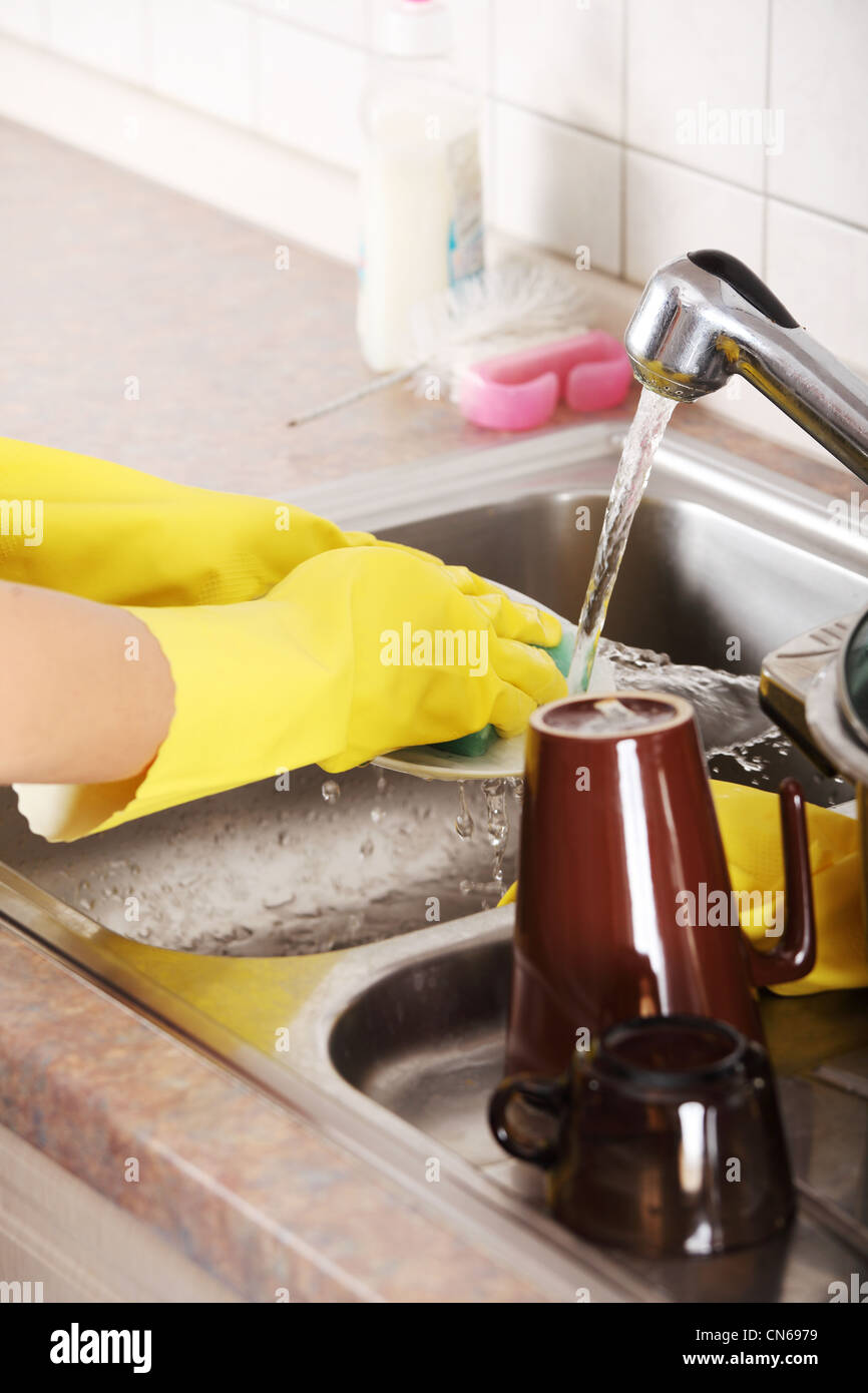 Hands in yellow glowes washing dish Stock Photo - Alamy