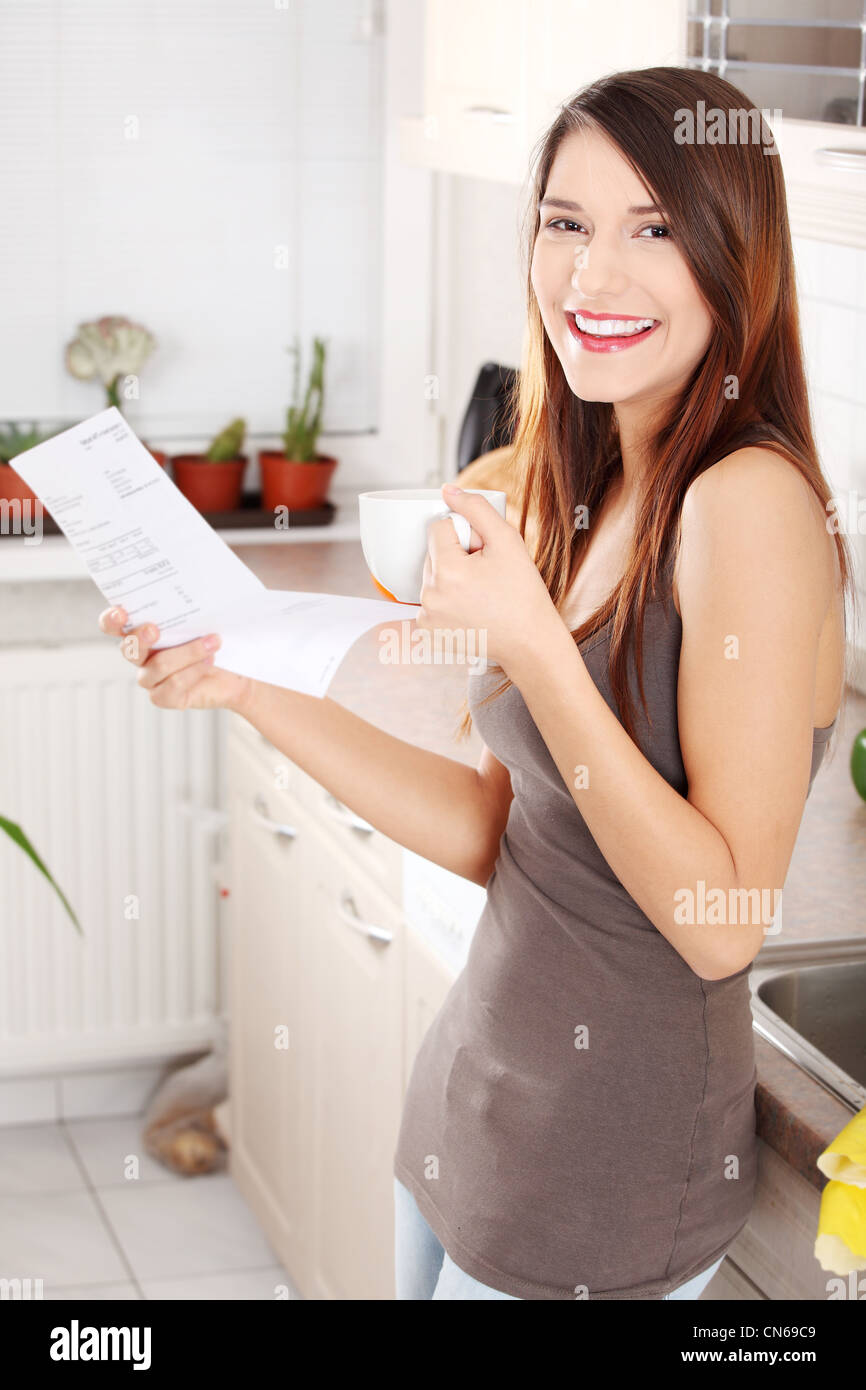 Beautiful young happy caucasian woman in the kitchen drinking something ...